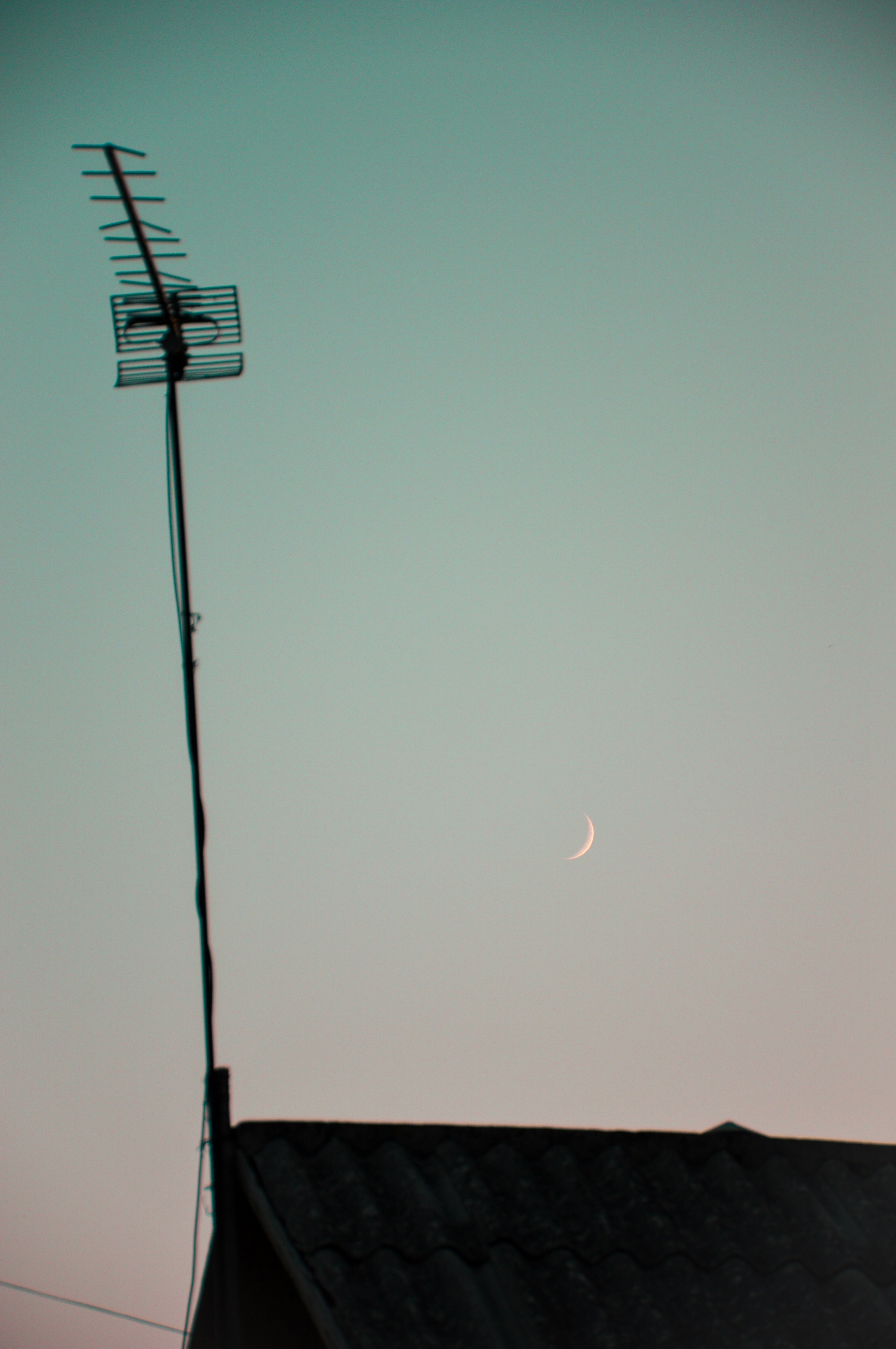 Moon Crescent Over Rooflines: A Quiet Dusk with a Rooftop Antenna