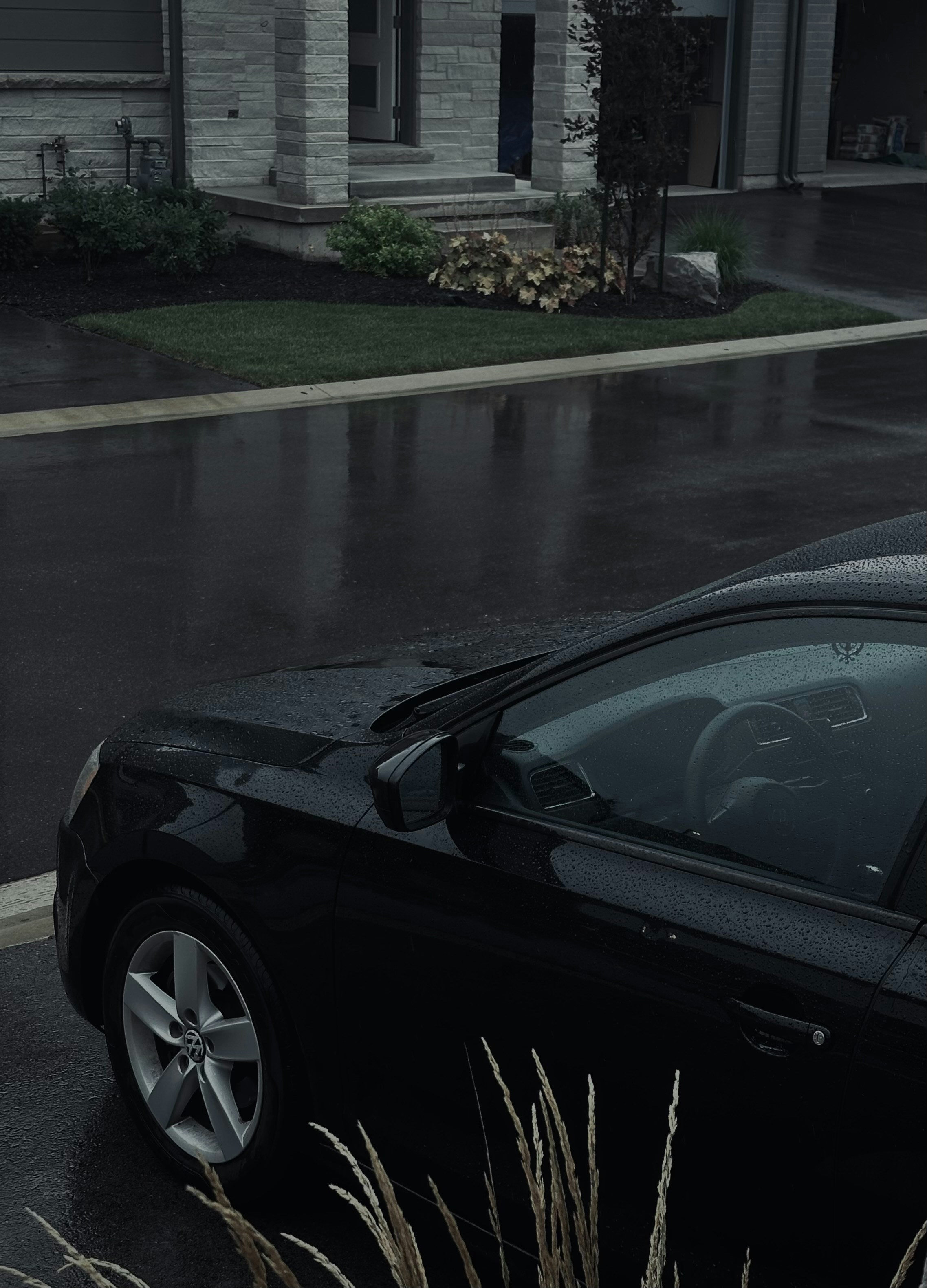 Rain-Kissed Noir: A Black Sedan Quietly Guarding a Suburban Driveway