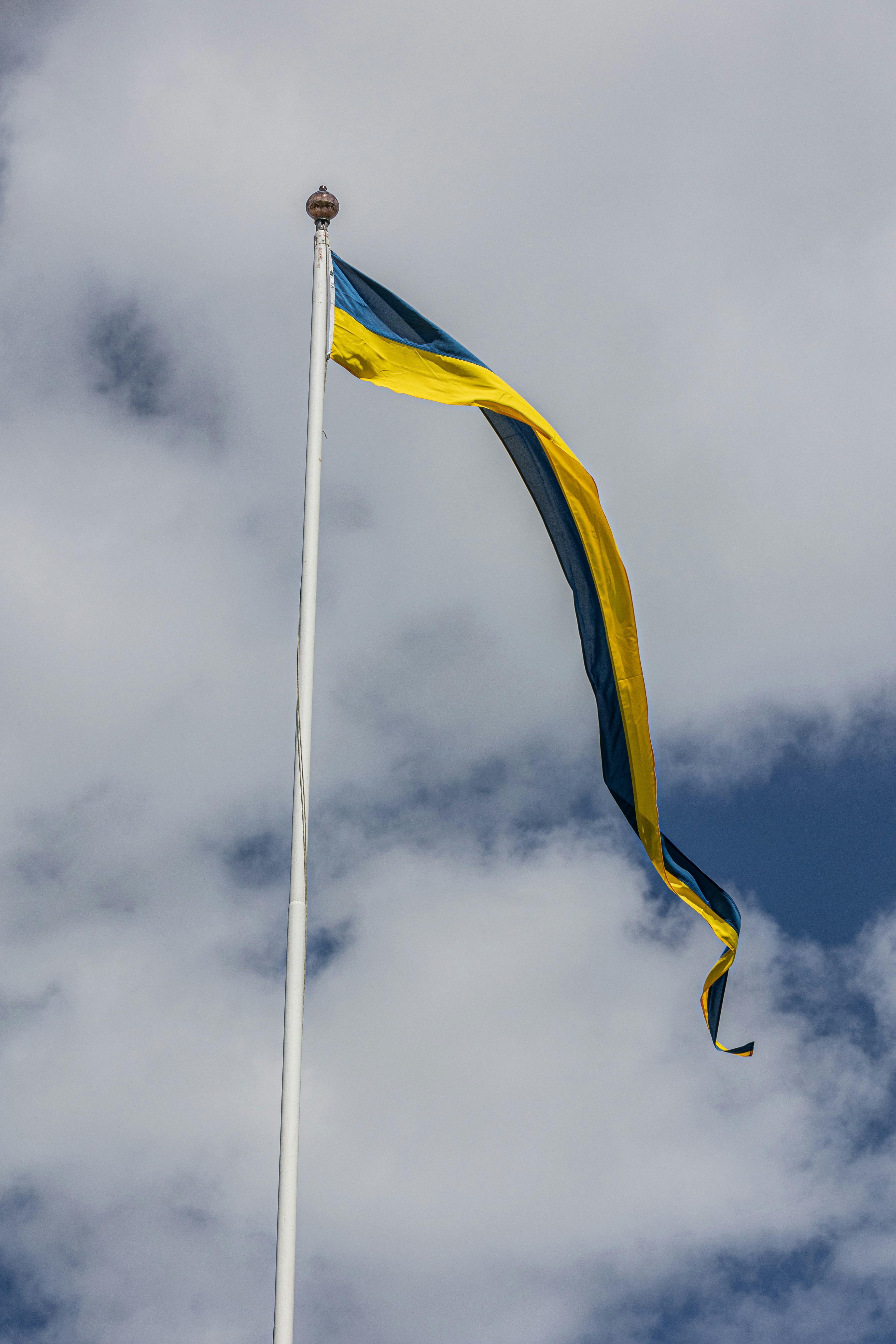 A yellow and blue flag is flying high in the sky photo – Free Flag ...