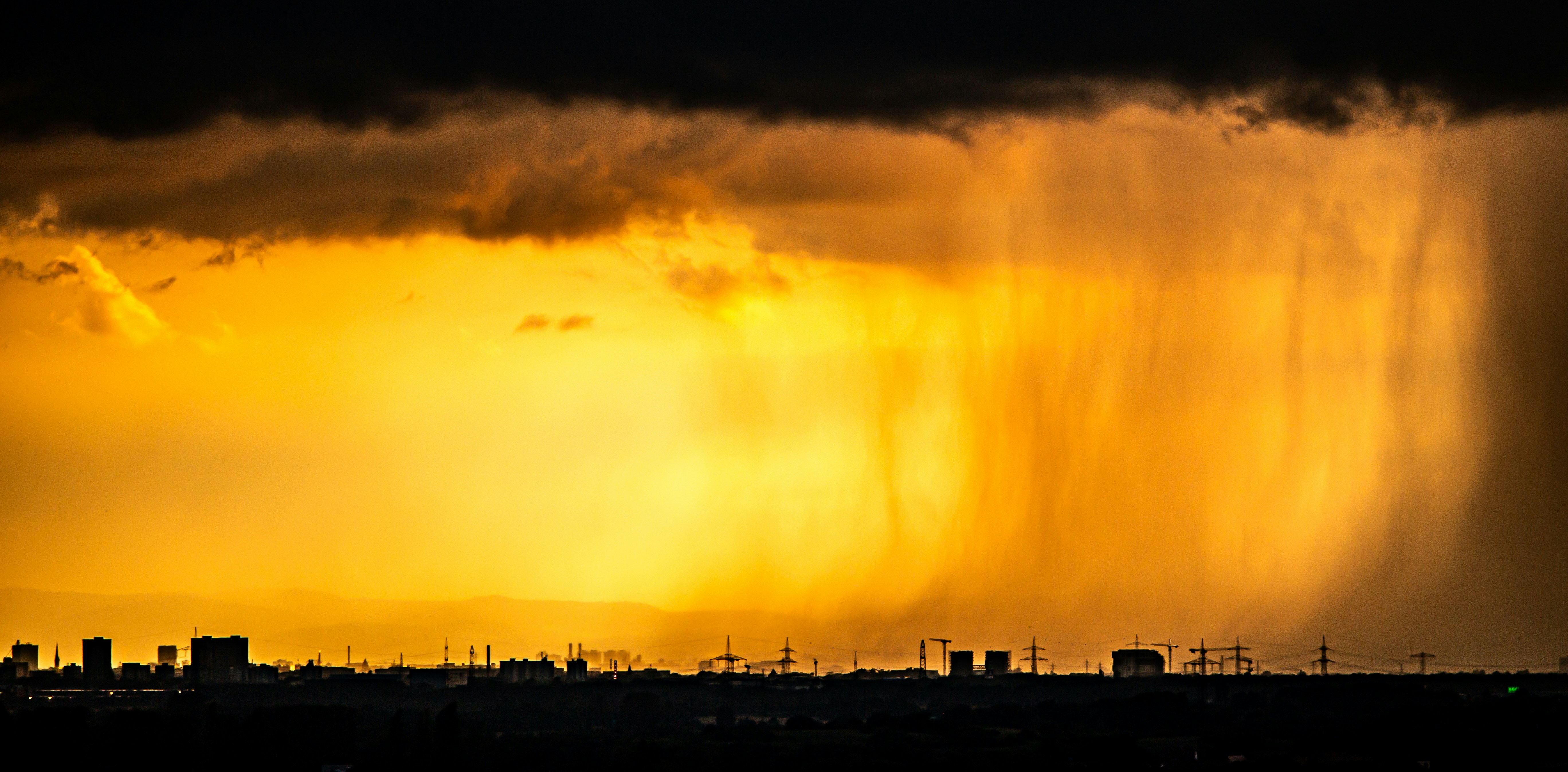 Gilded Horizon: Rain Veil Over a Silent Industrial Skyline at Dusk