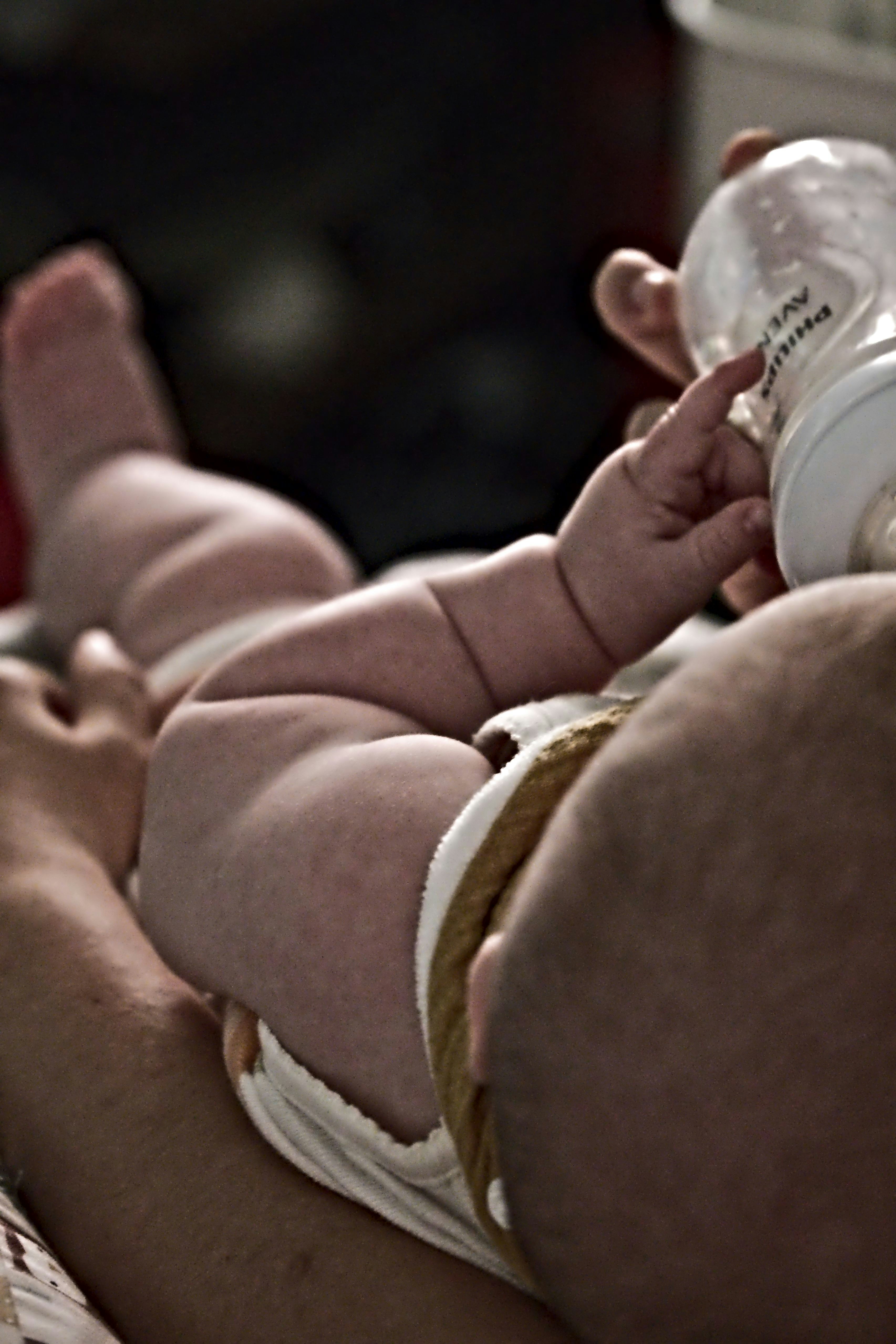 A person holding a baby with a bottle in their hand