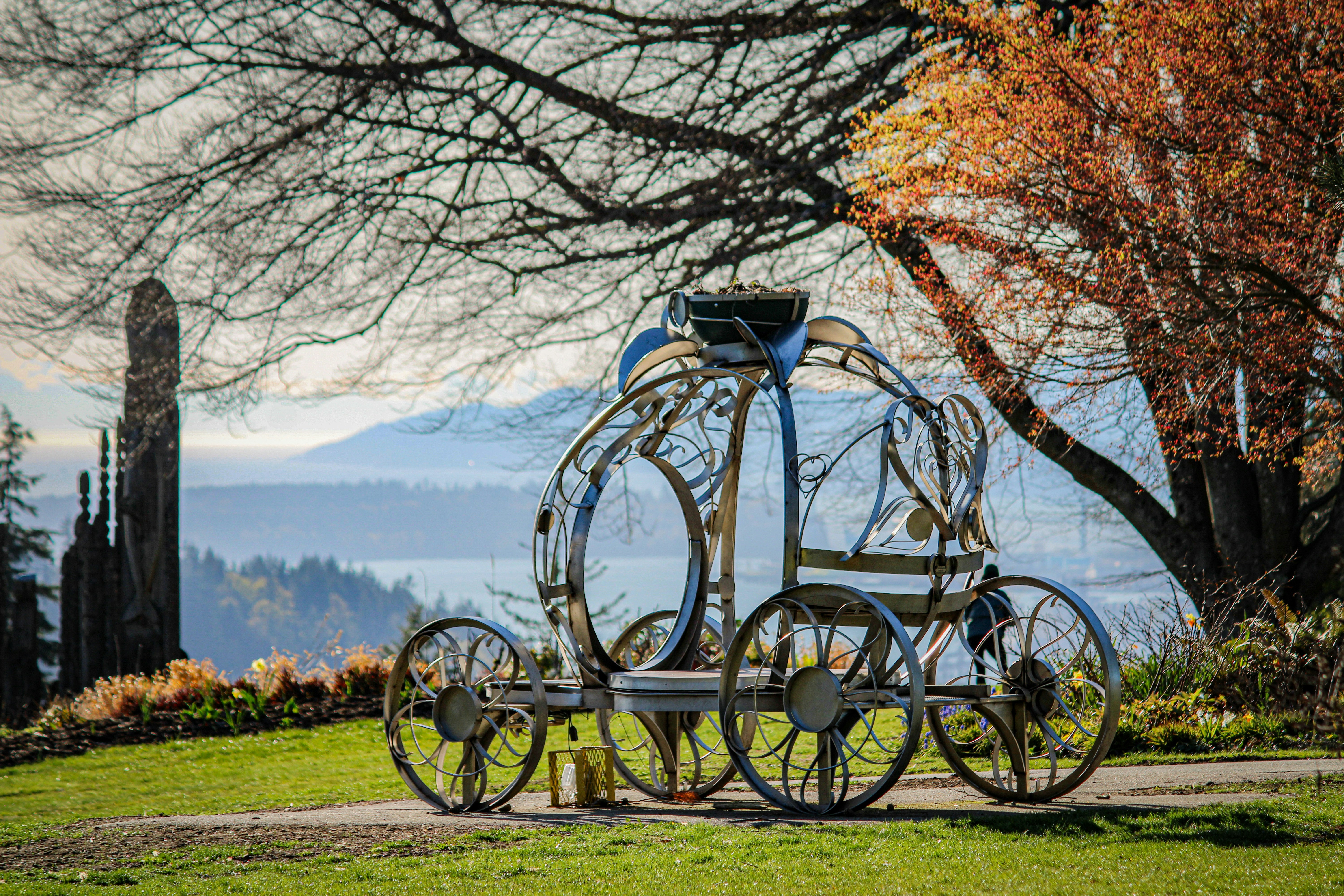 Iron Echoes in Autumn Light: A Carriage Sculpture Amid Maple Canopies