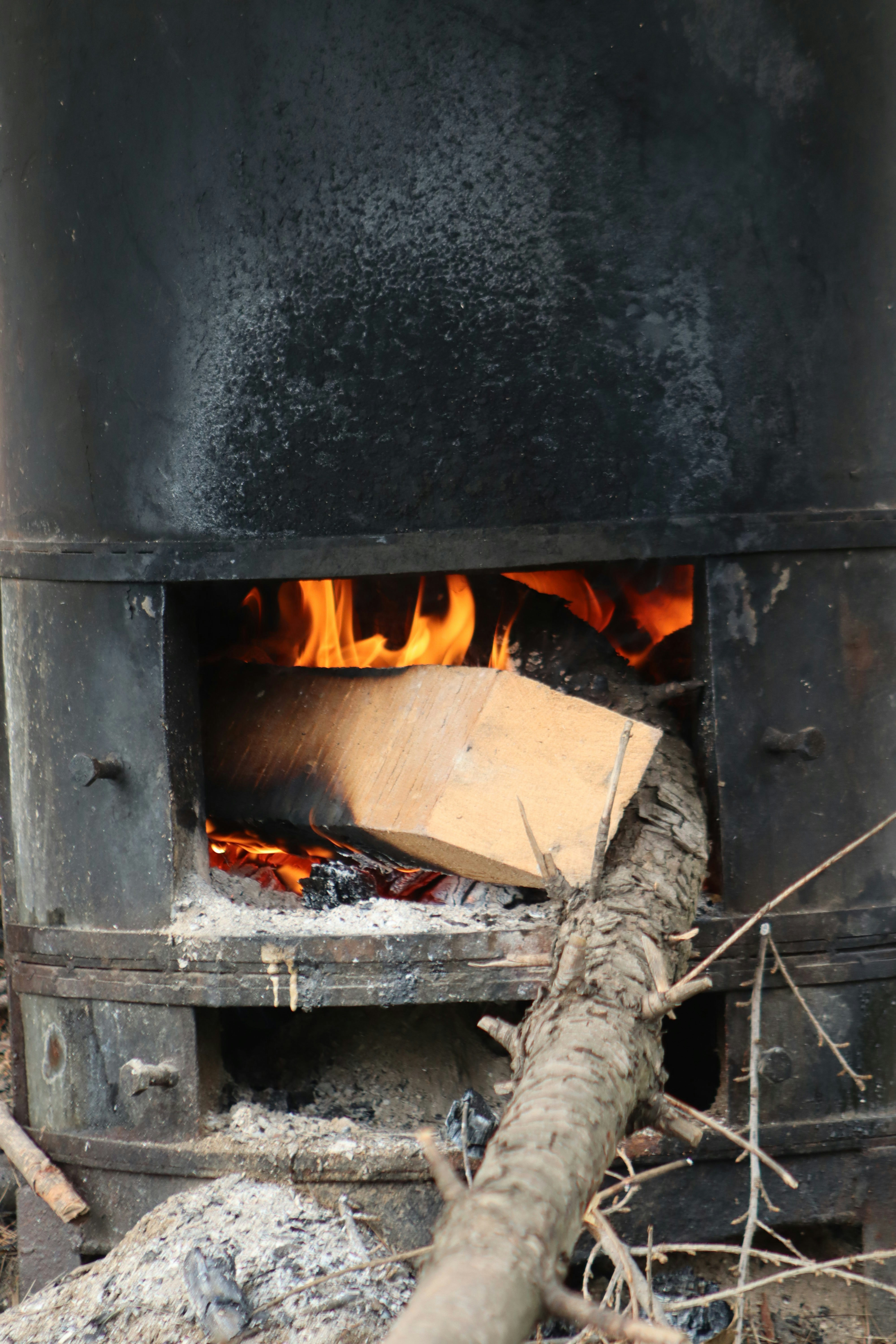 Flames dance around a log in a rustic stove, showcasing the warmth and energy of a traditional cooking method.