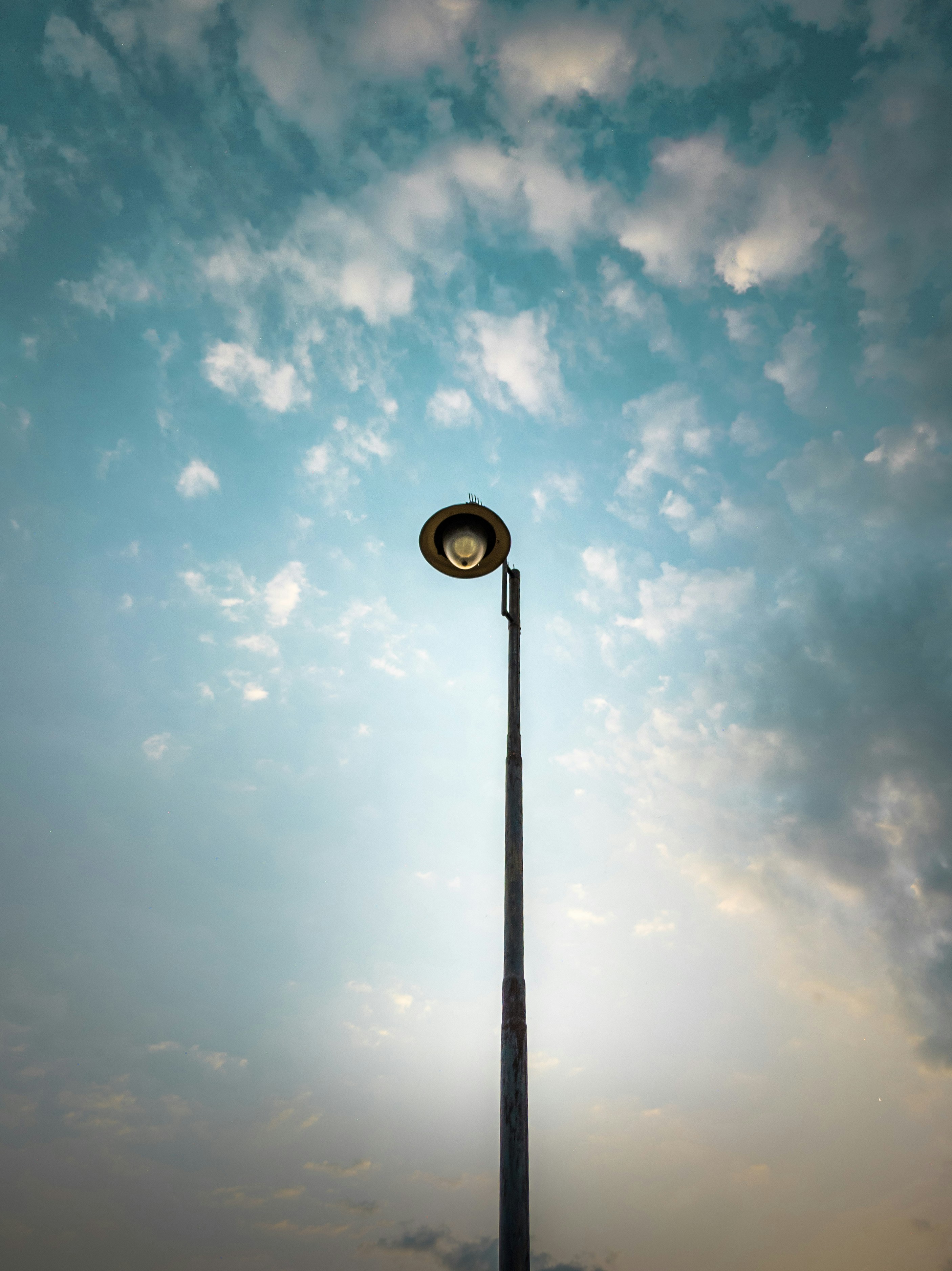 Streetlight silhouetted against a vibrant, cloud-filled sky.