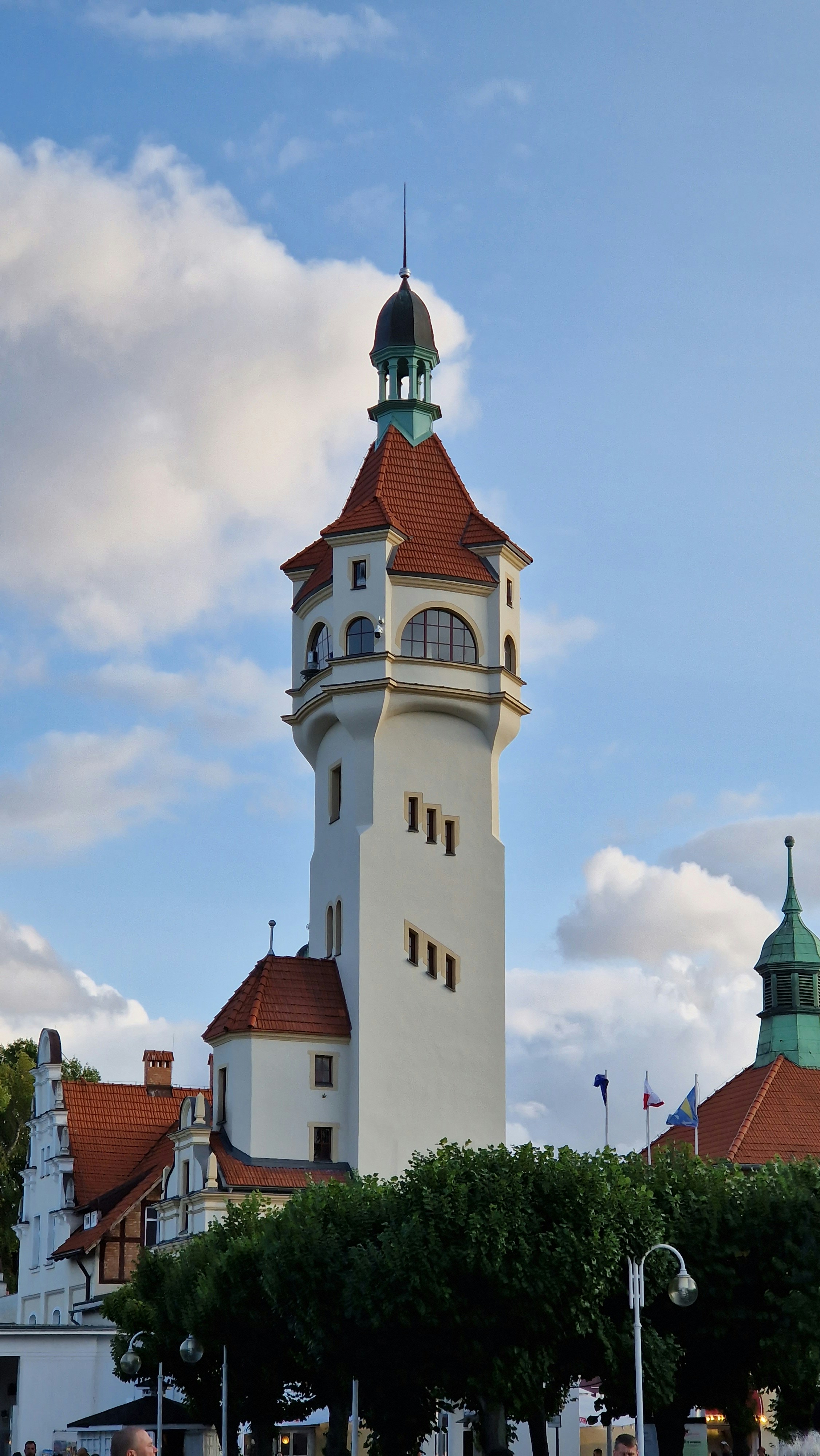Crowned Spire: A Pale European Tower with Crimson Roof Against a Clear Sky
