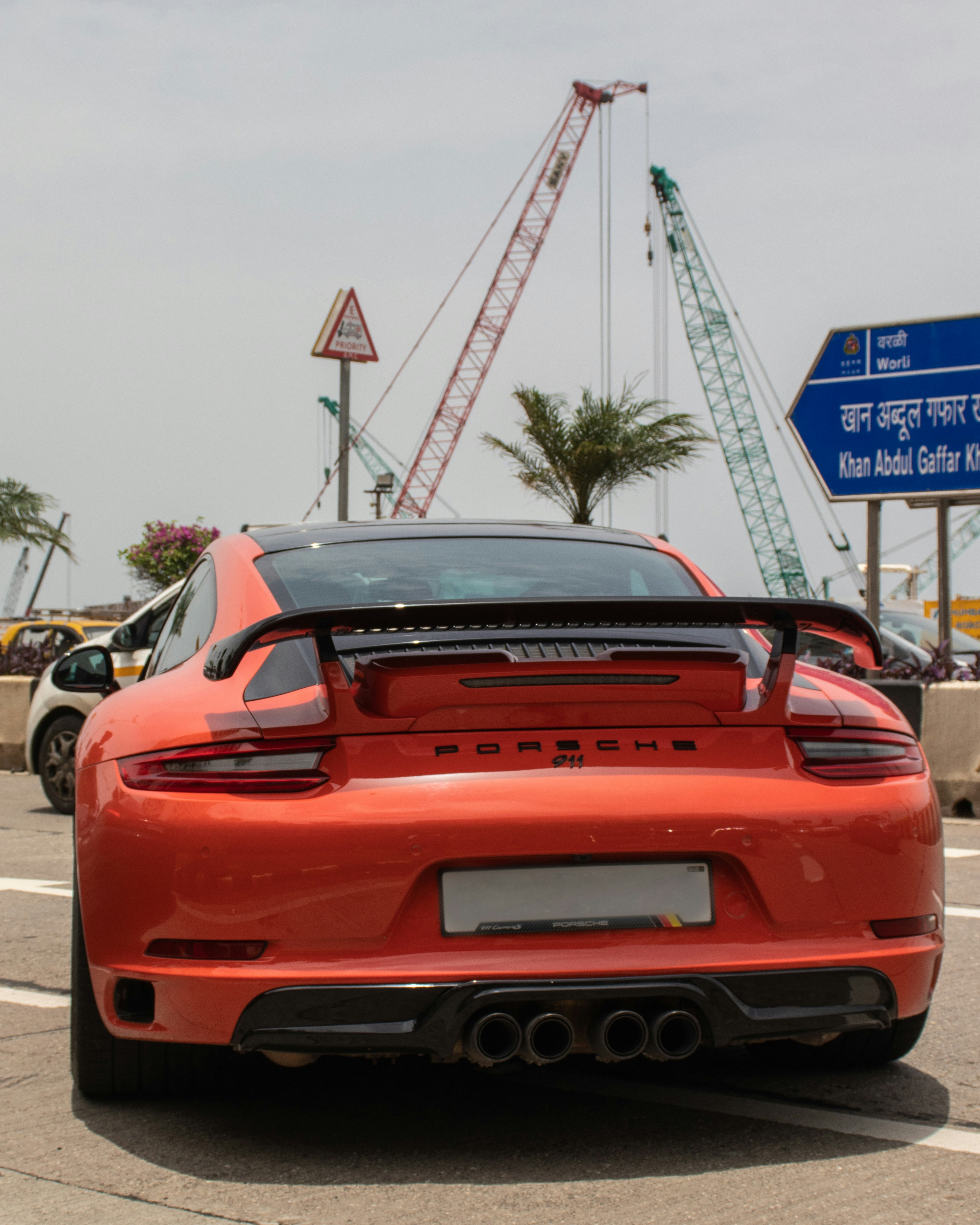 Rear-View Pose: Scarlet Porsche Dominates a Harborfront Construction Scene
