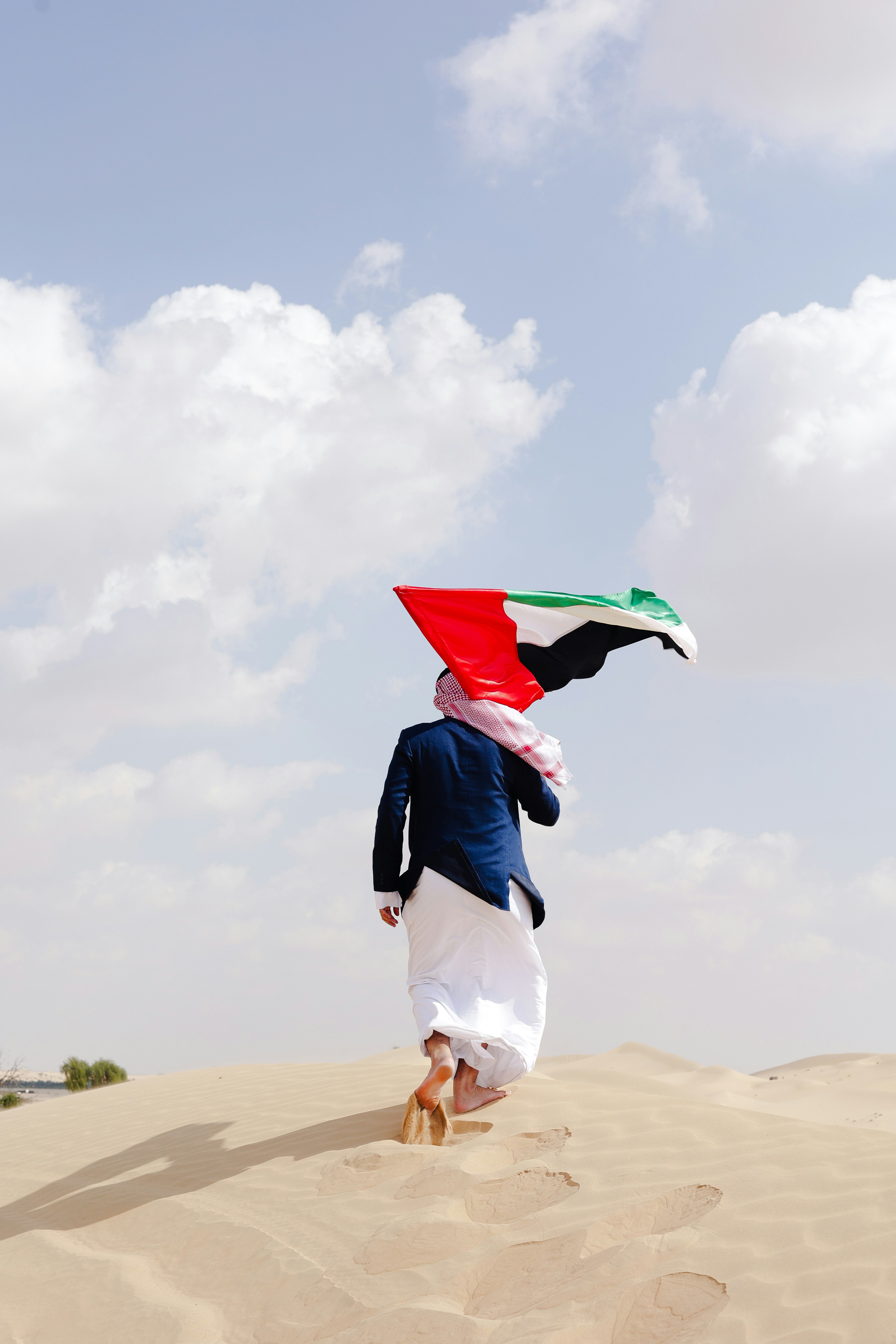 Tri-Color Flag Dances Above a Barefoot Wanderer on Desert Dunes