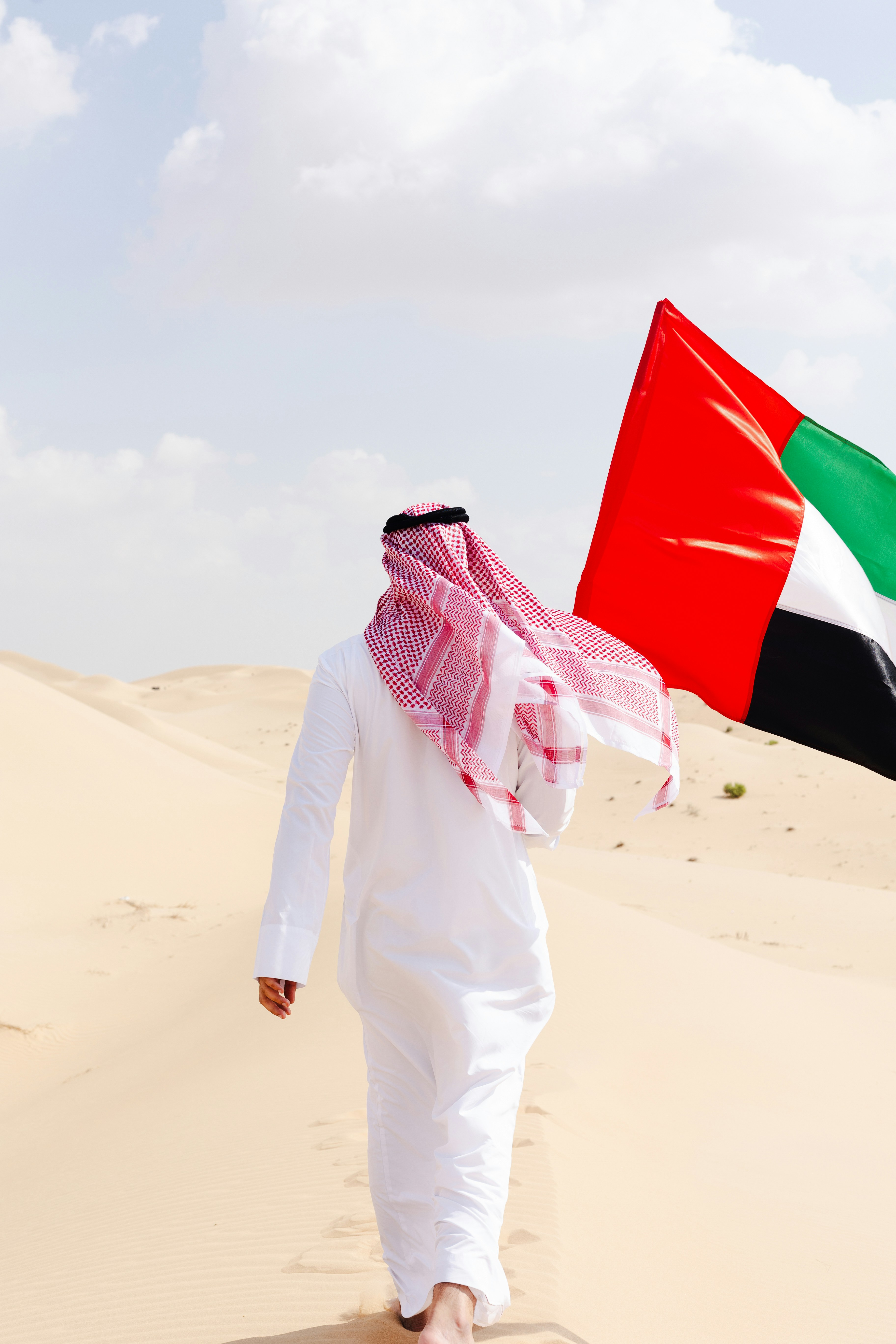 Desert Banner: A Man in White With Flag Crossing Dunes