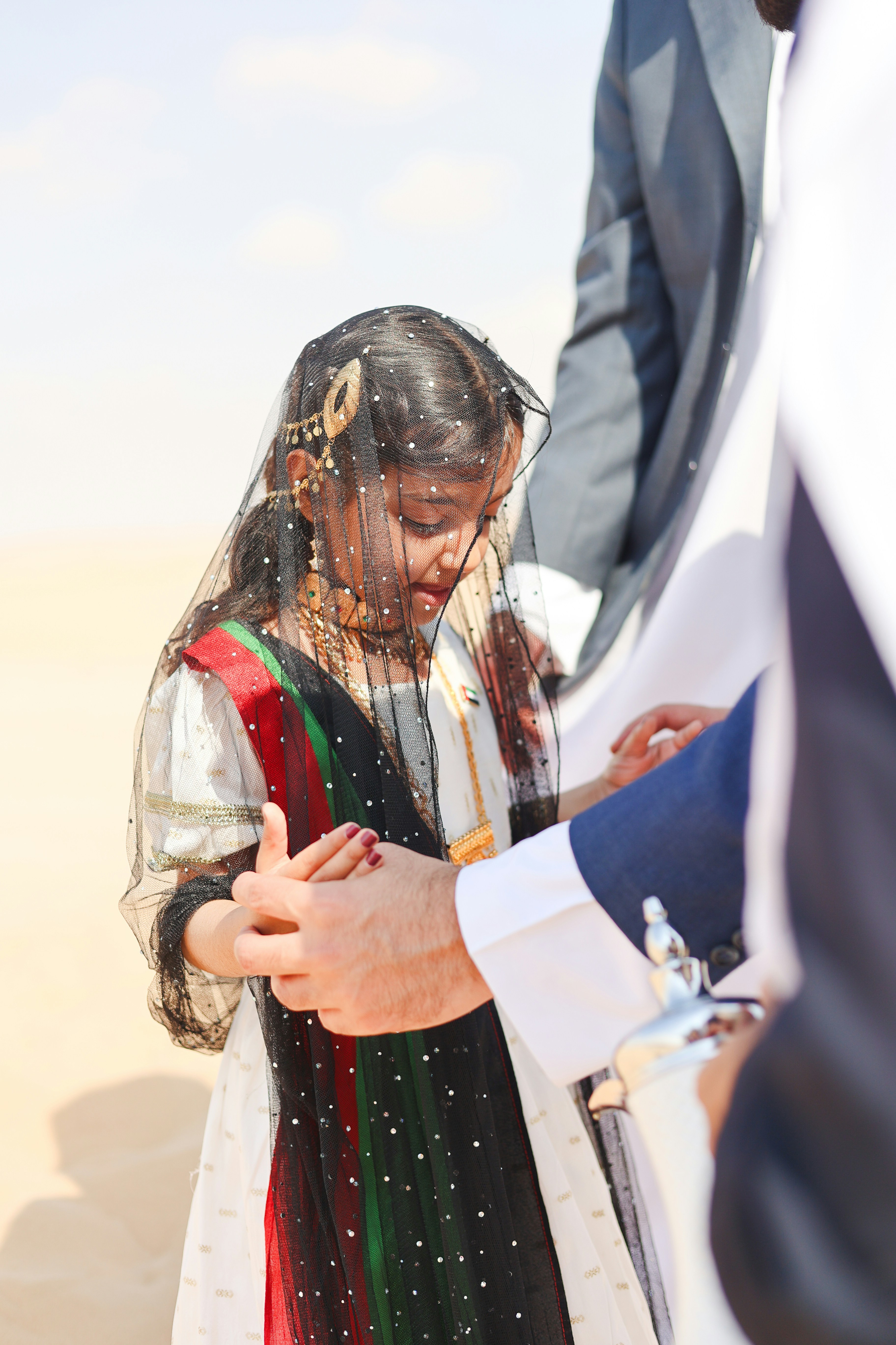 Veiled Ceremony: A Child in Traditional Dress at a Blessing