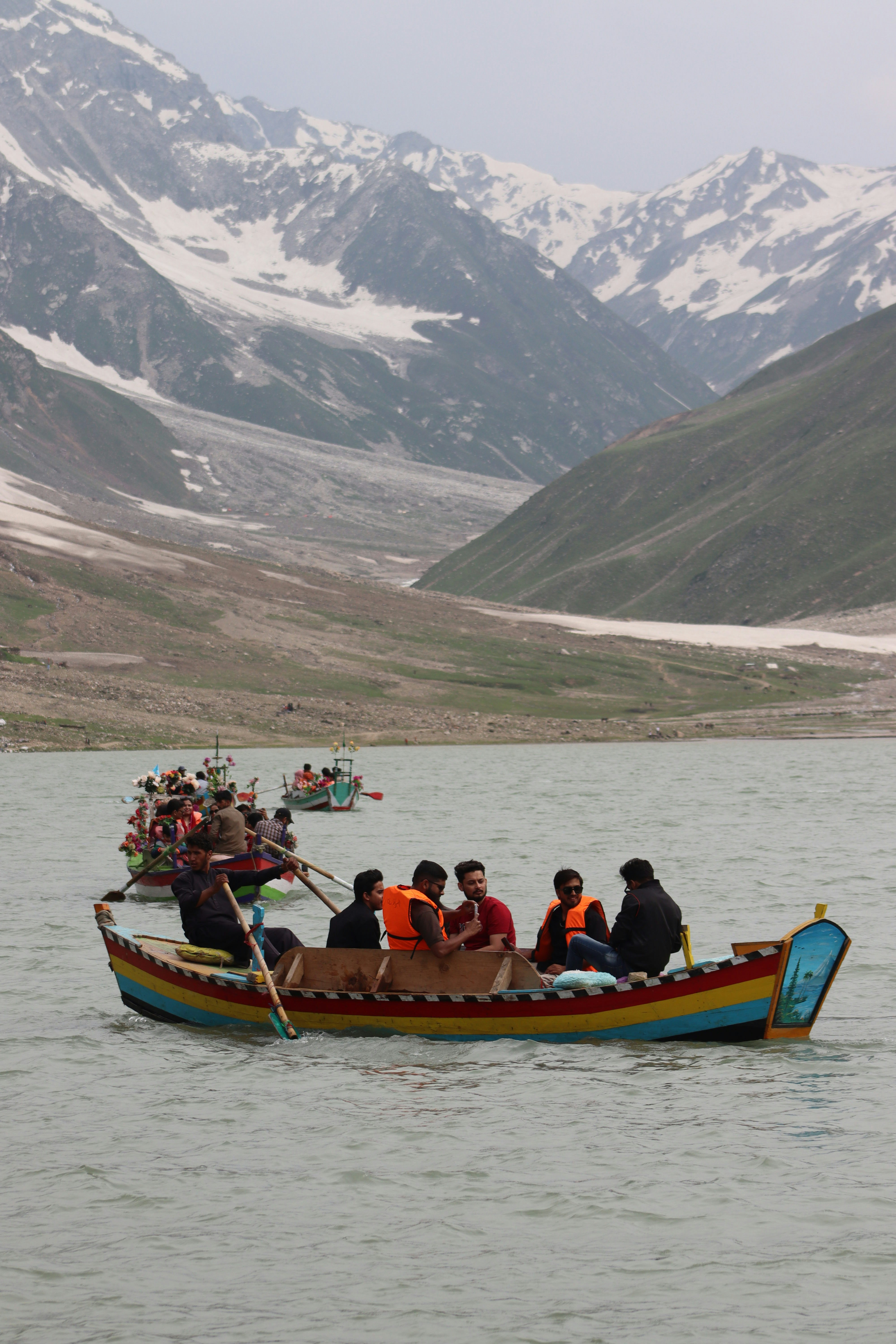 Colorful Boat Crossing a Turquoise Glacial Lake Beneath Snowy Peaks