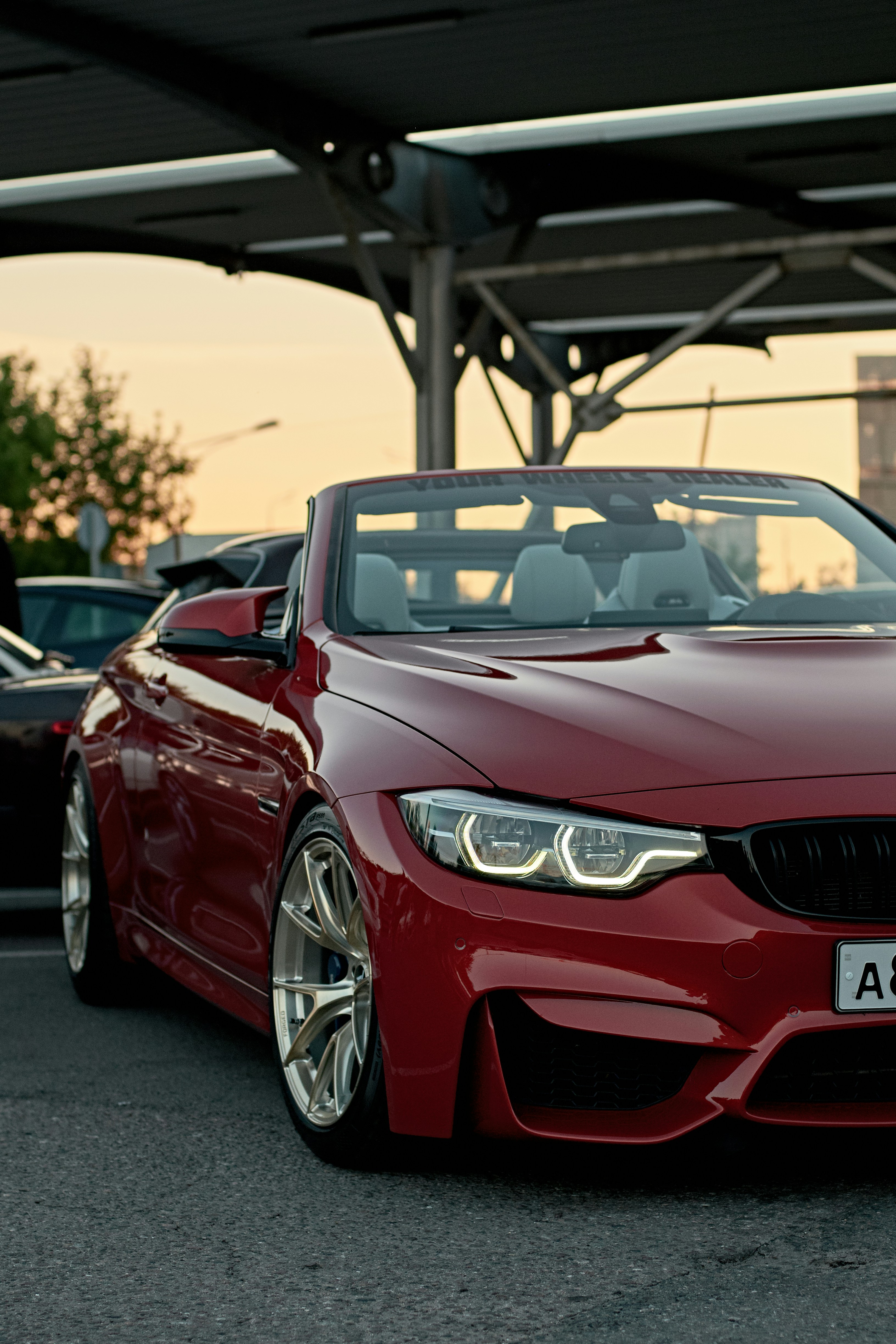 Sleek red convertible parked under a canopy, showcasing its stylish curves and modern design against a soft evening backdrop.