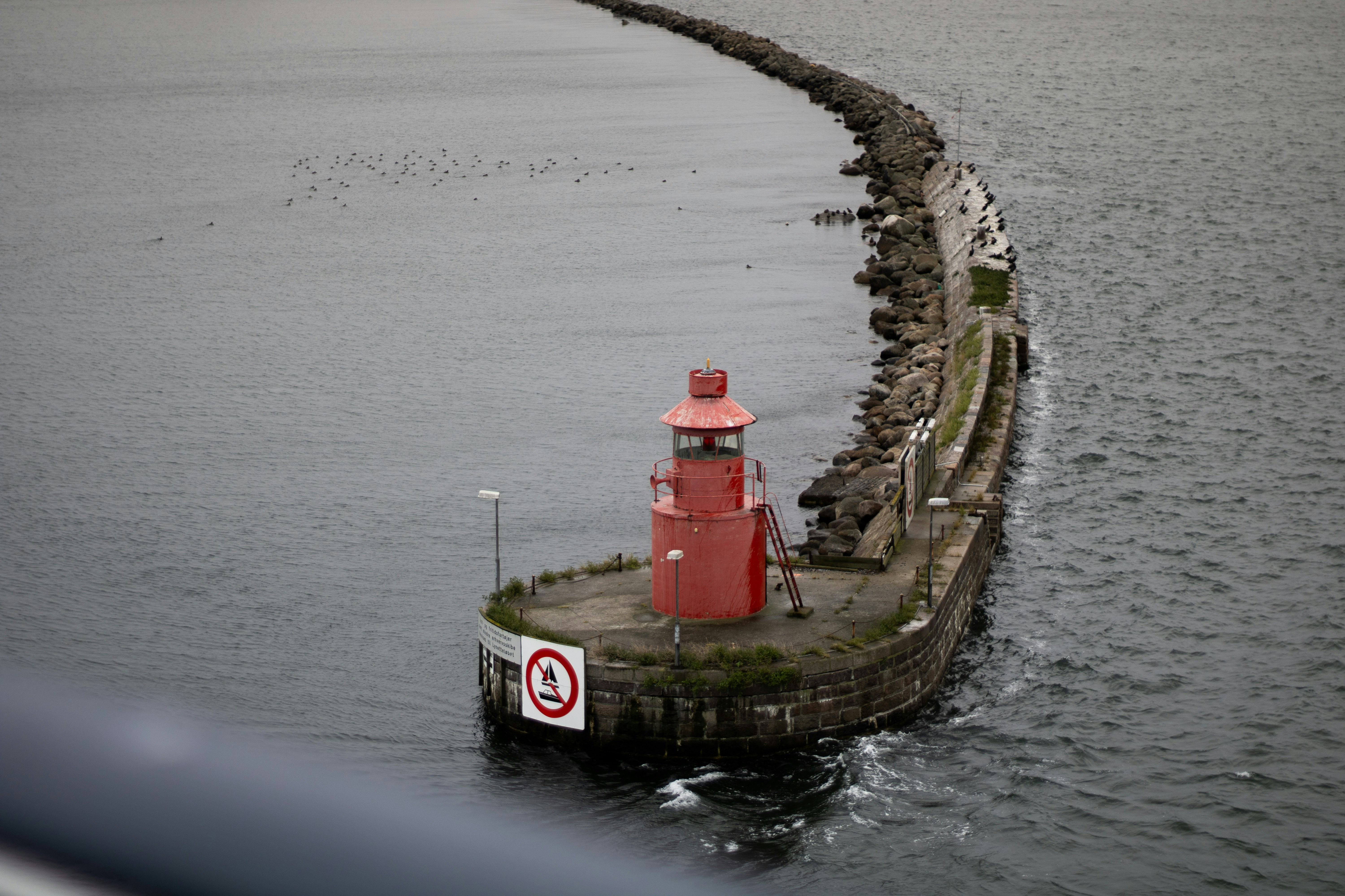 Scarlet Beacon on a Curved Breakwater