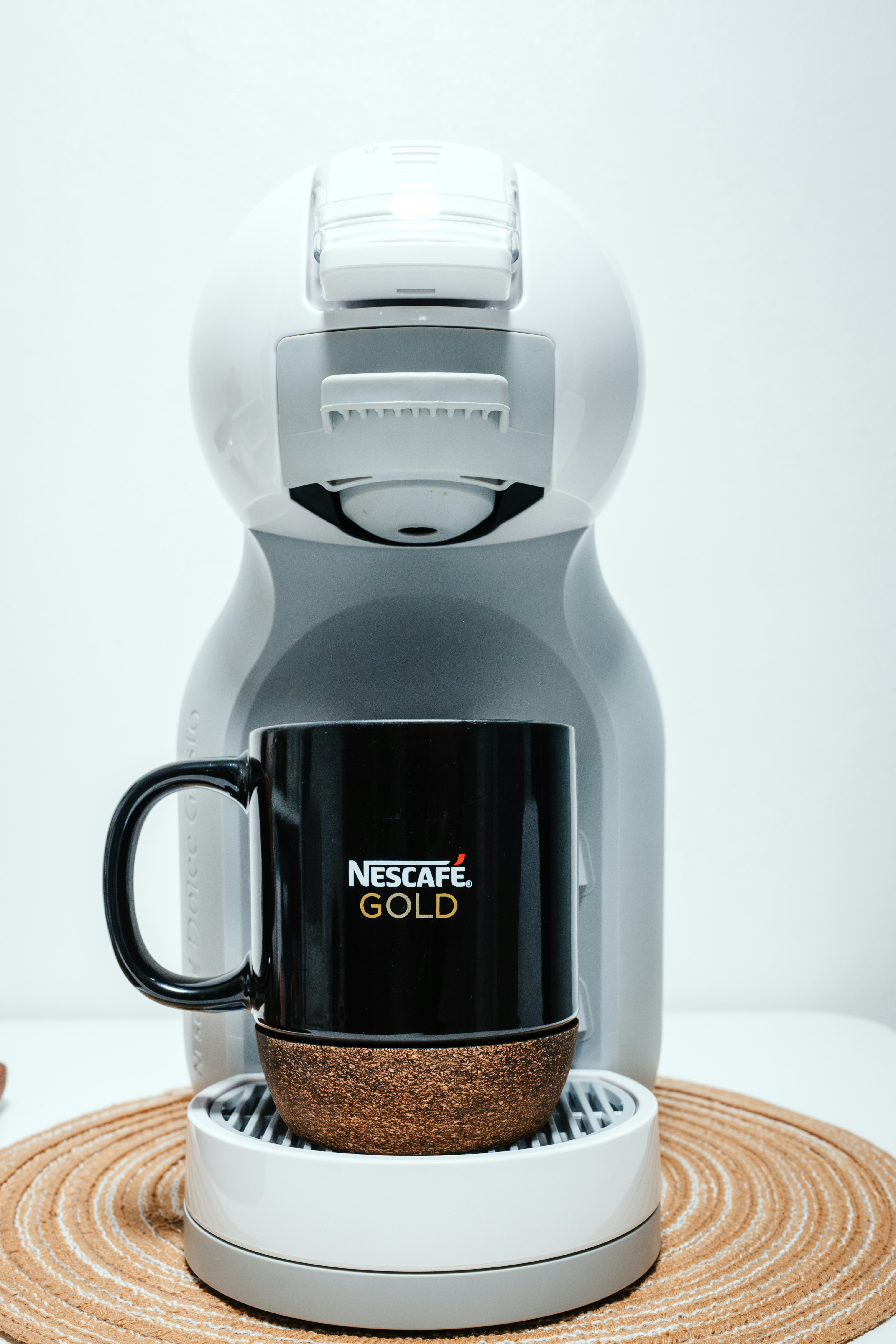 A coffee cup sitting on a coaster next to a coffee maker photo – Free ...