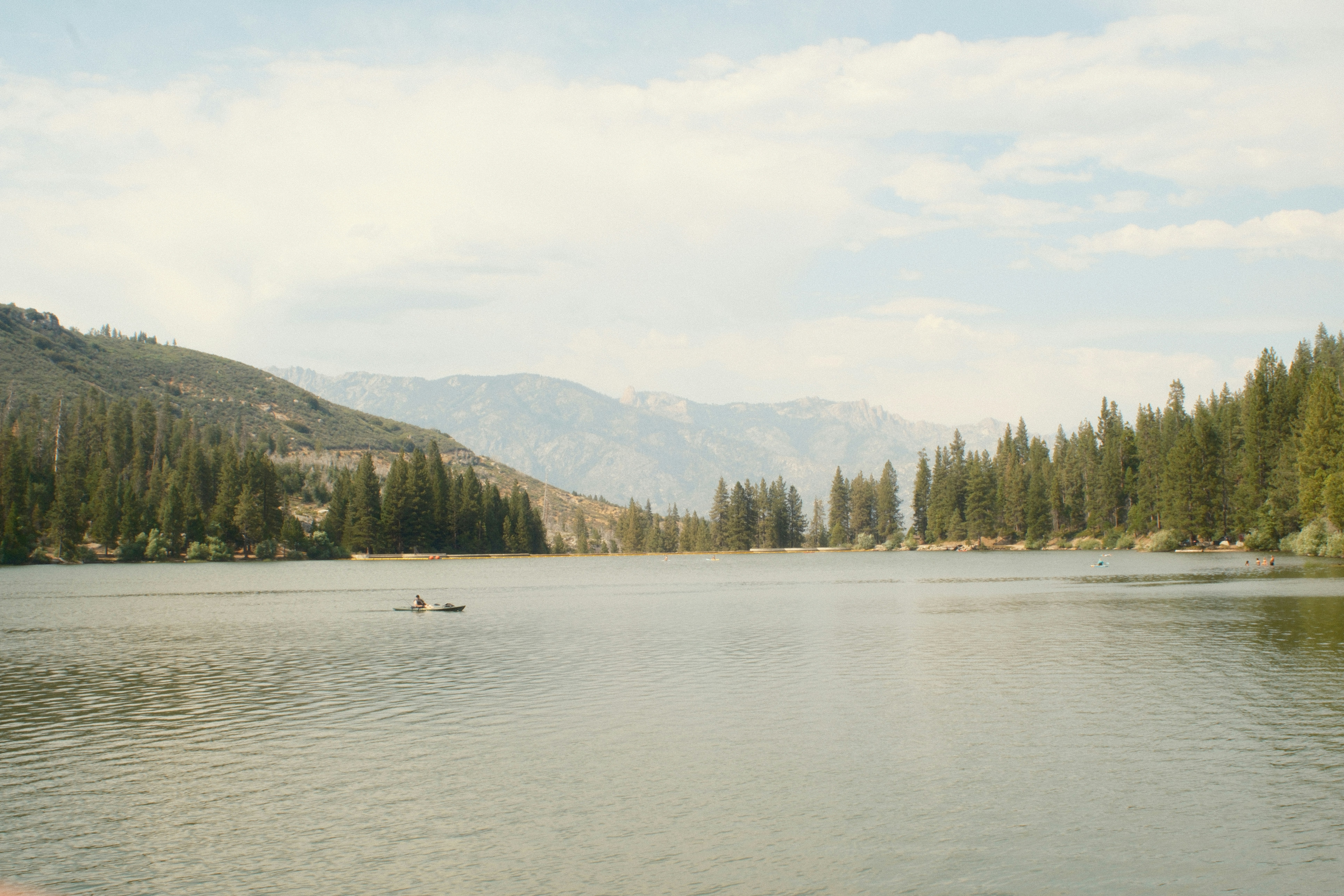Lone Rowboat on a Glassy Alpine Lake Beneath Pine-Crowned Valleys