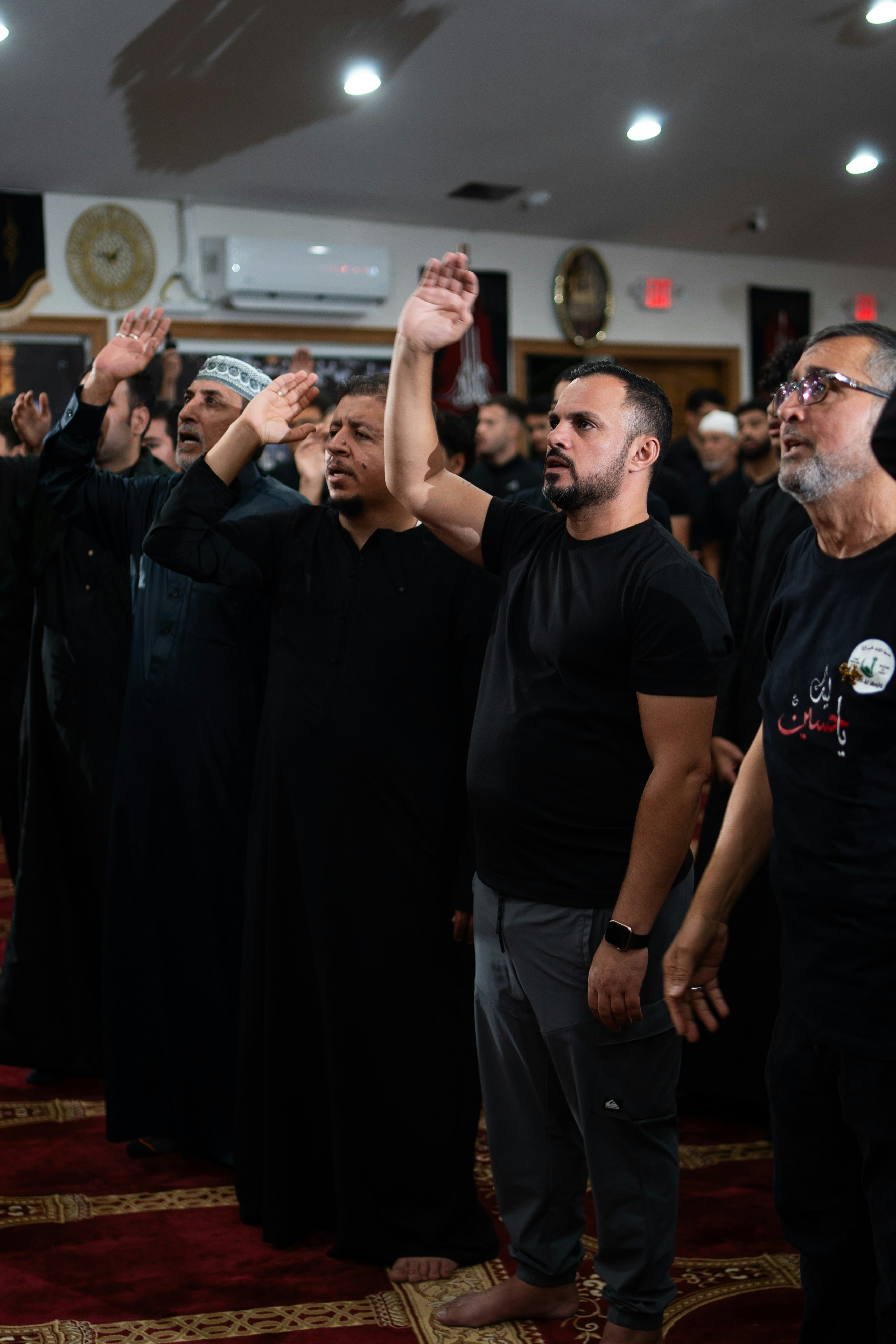 Raised Hands in a Silent Hall: A Collective Moment in Black Attire