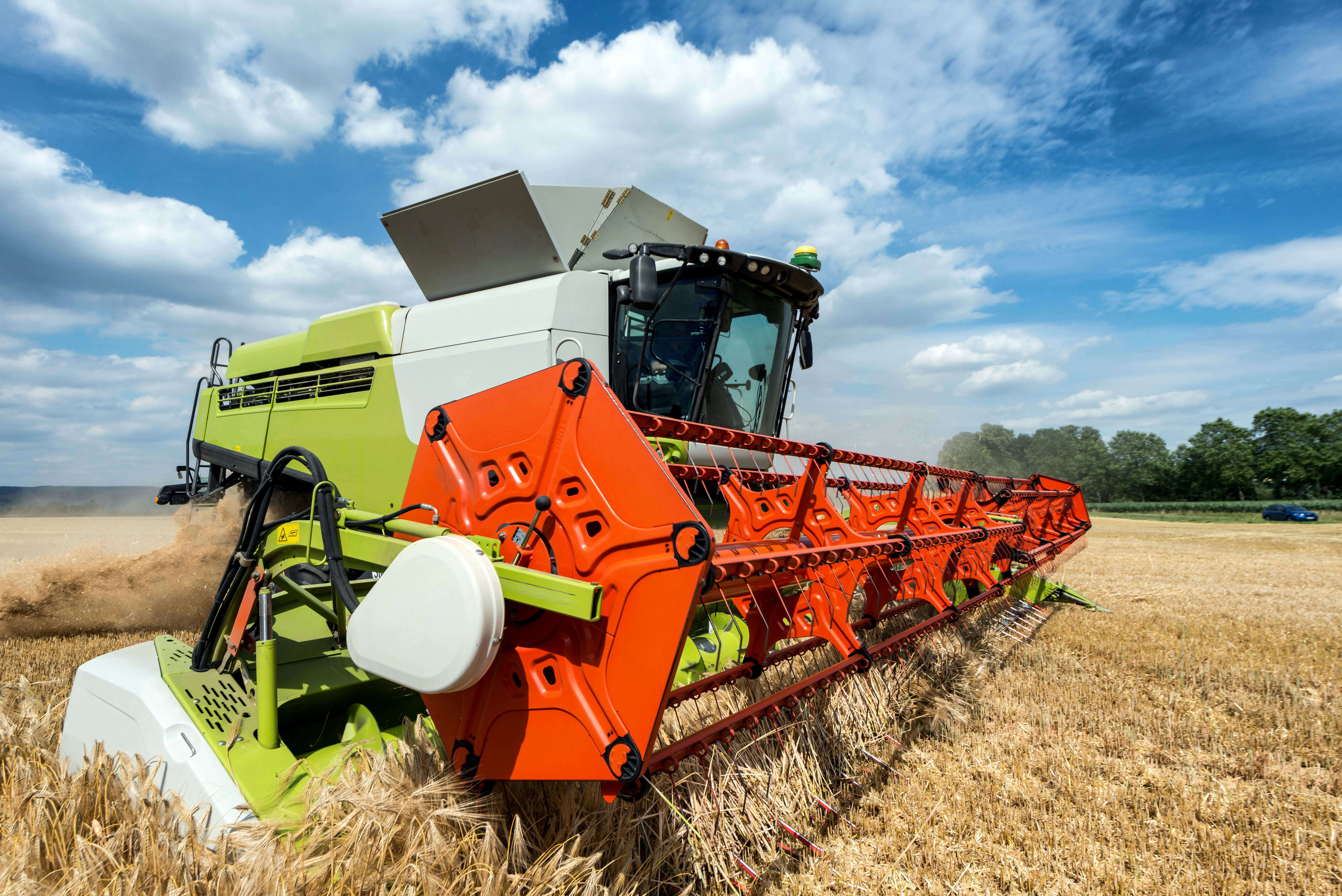 A green and orange combine in a wheat field photo – Free Deutschland ...
