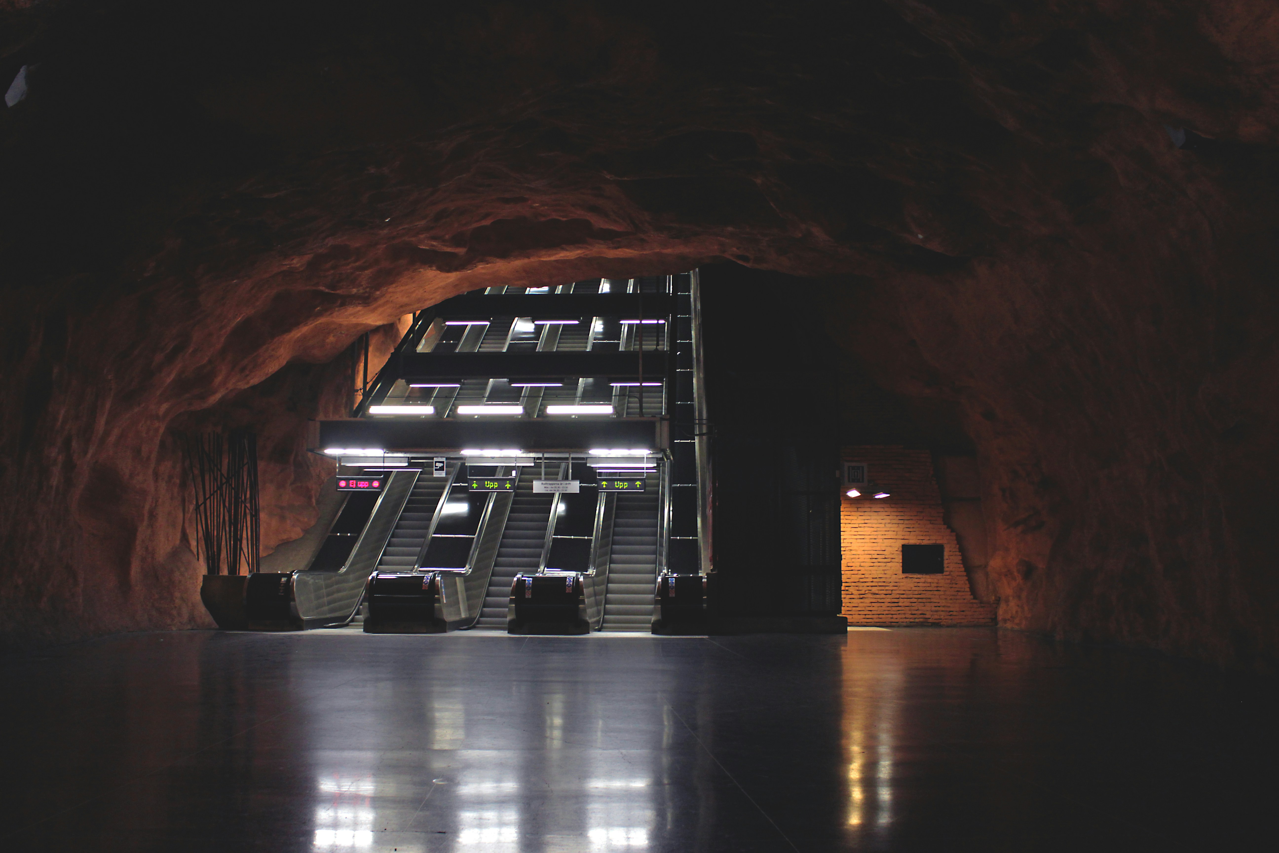 Neon Escalators in a Cavern: A Quiet Ascent Along a Glossy Underground Chamber