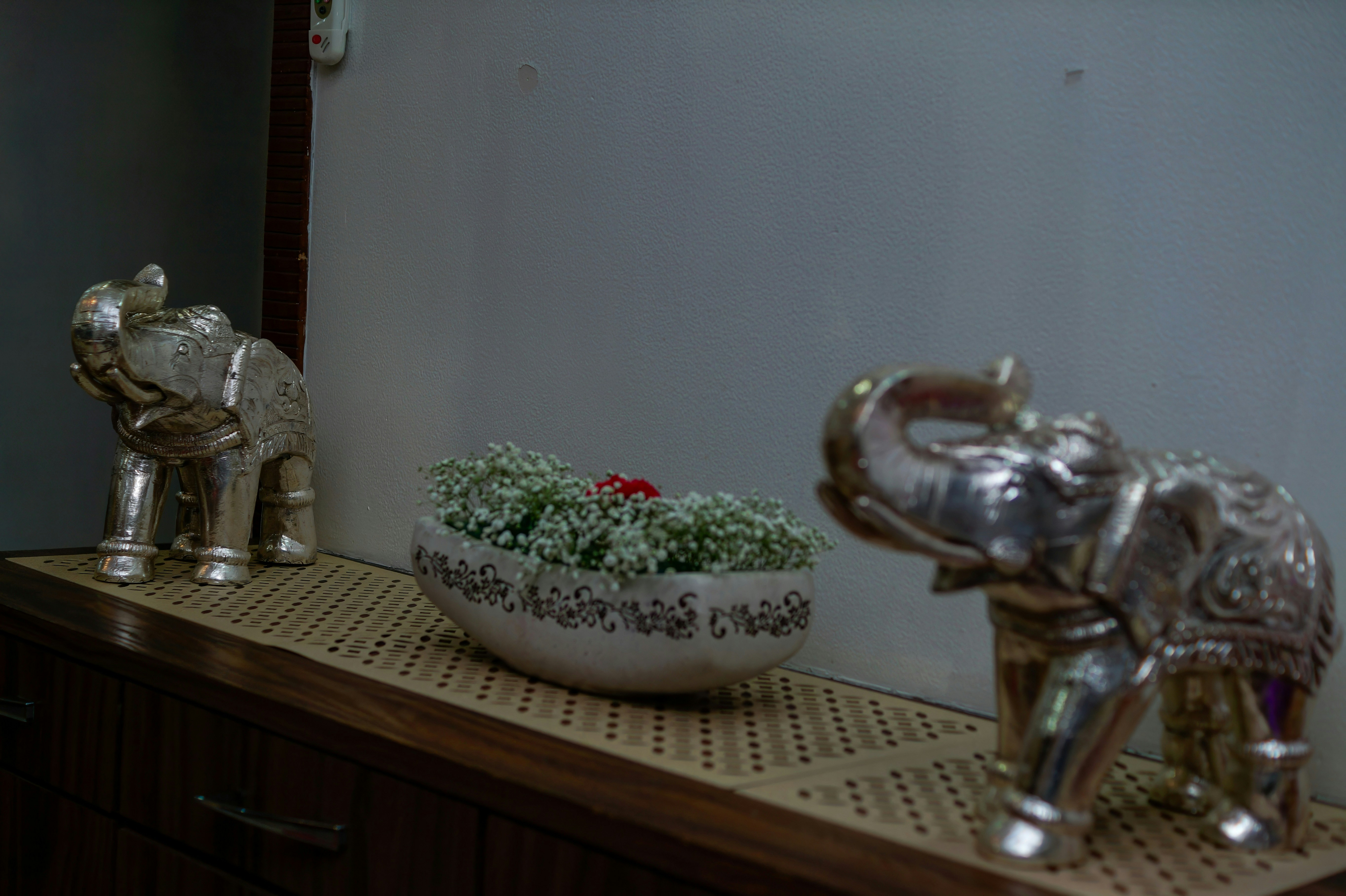 Delicate Blooms Framed by Silver Elephants on a Perforated Shelf