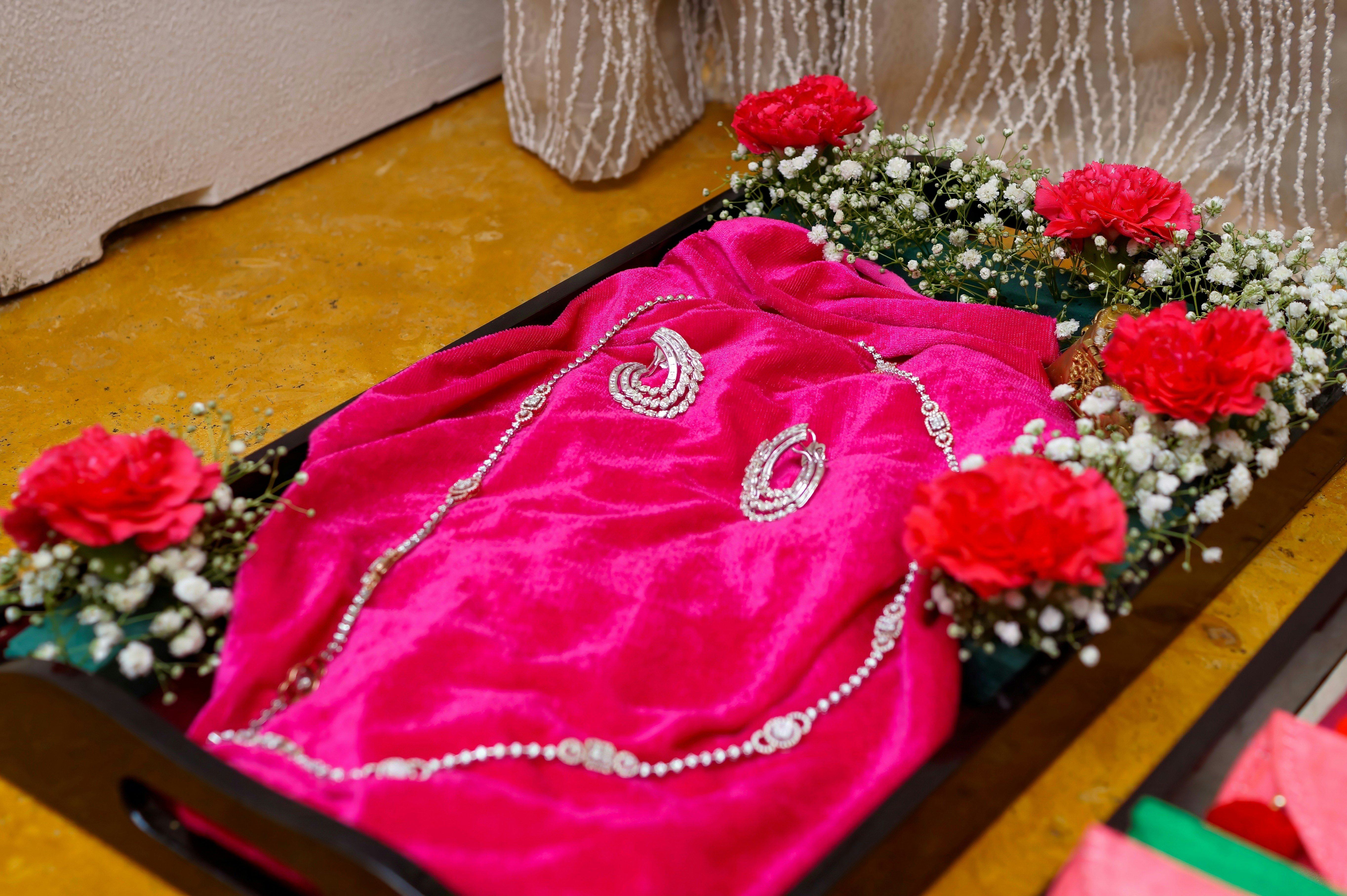 Crimson Velvet and Pearls: Jewelry Draped Across a Floral Casket