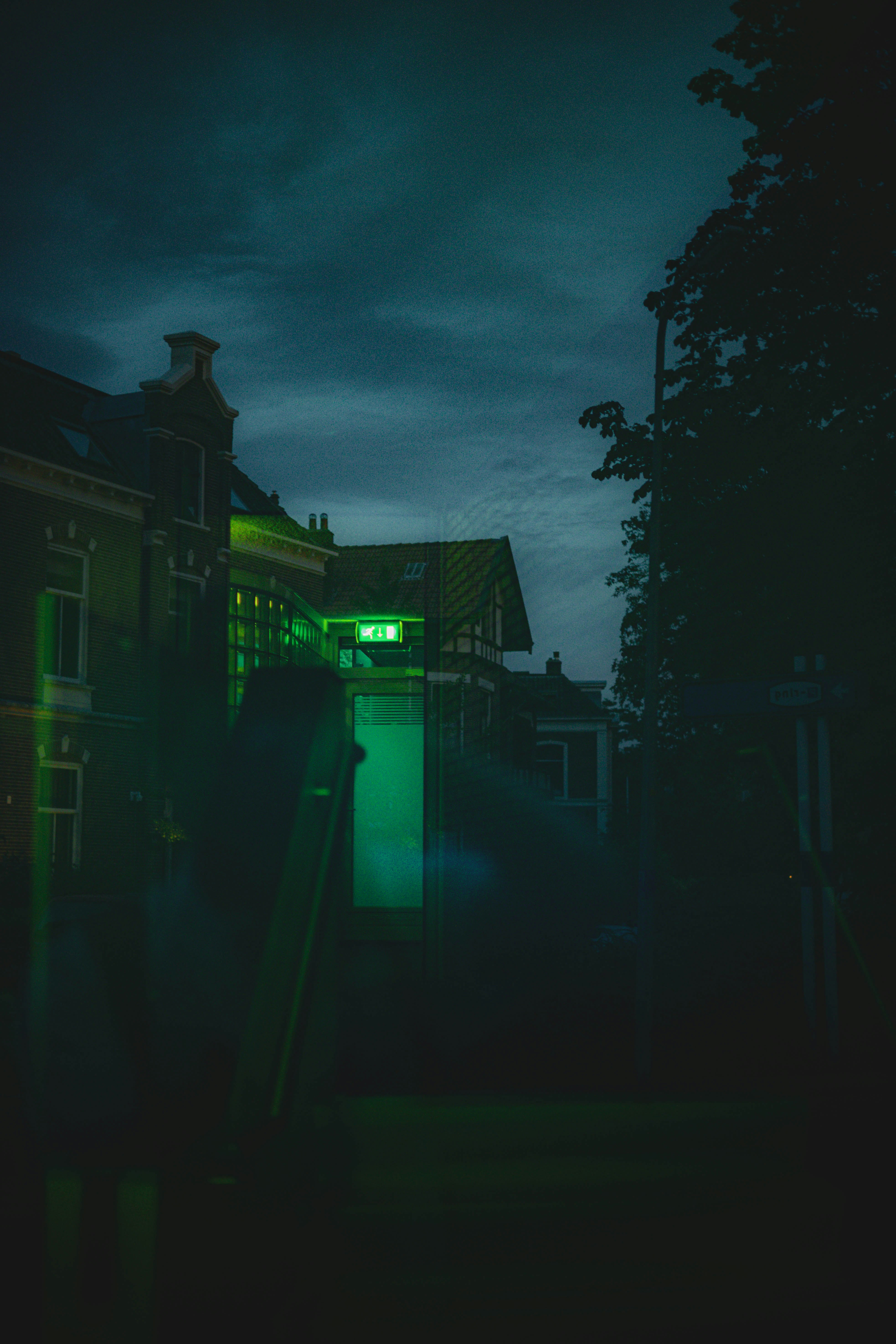 Emerald Threshold: Neon Exit Looms Over a Quiet Night Street