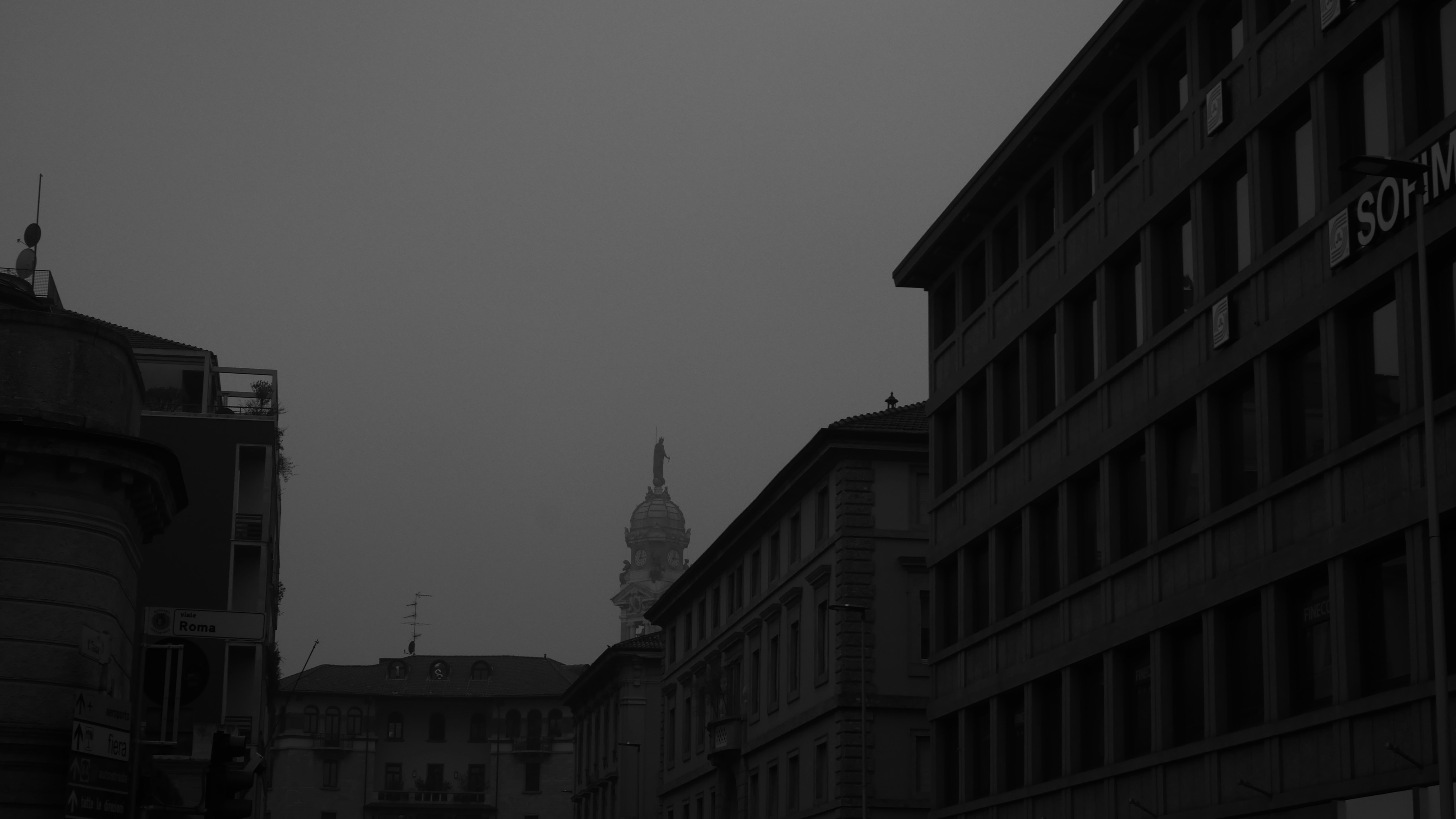 Distant Crown in Gray: a statue-topped building anchors a quiet urban canyon