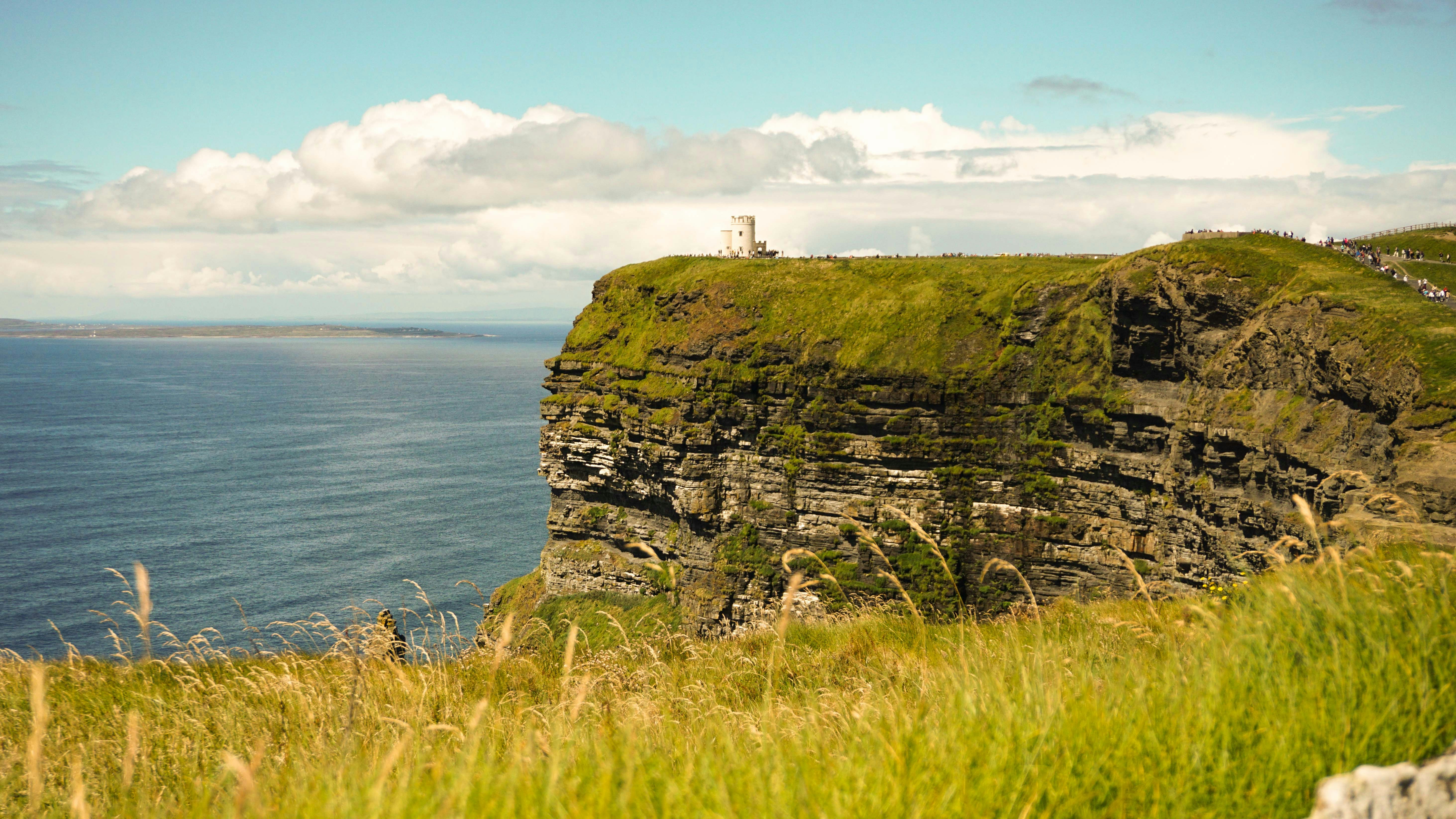A grassy field next to a cliff overlooking the ocean photo – Free Land ...