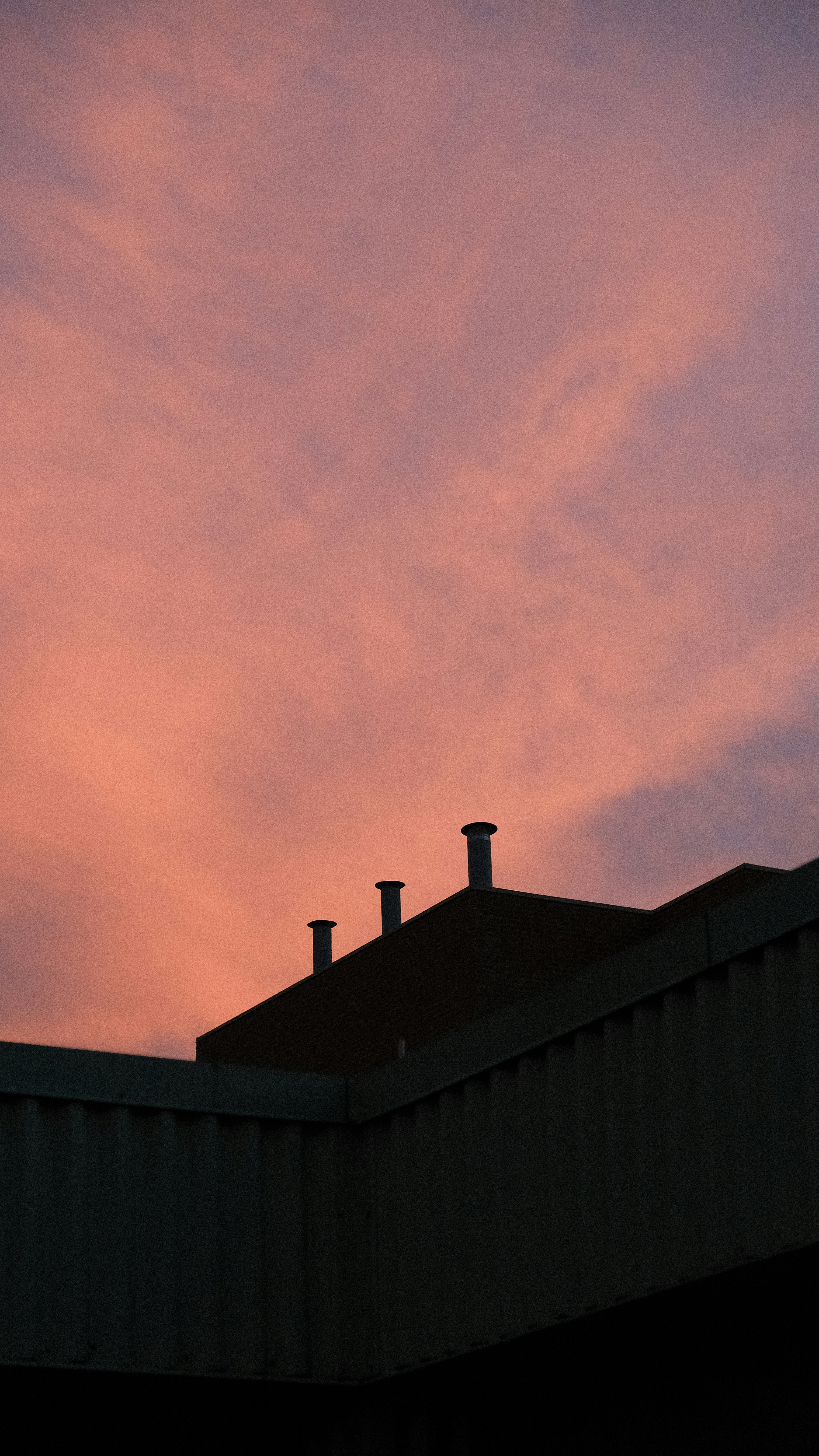 Chimney Row at Dusk: Coral Sky Drapes a Quiet Rooftop