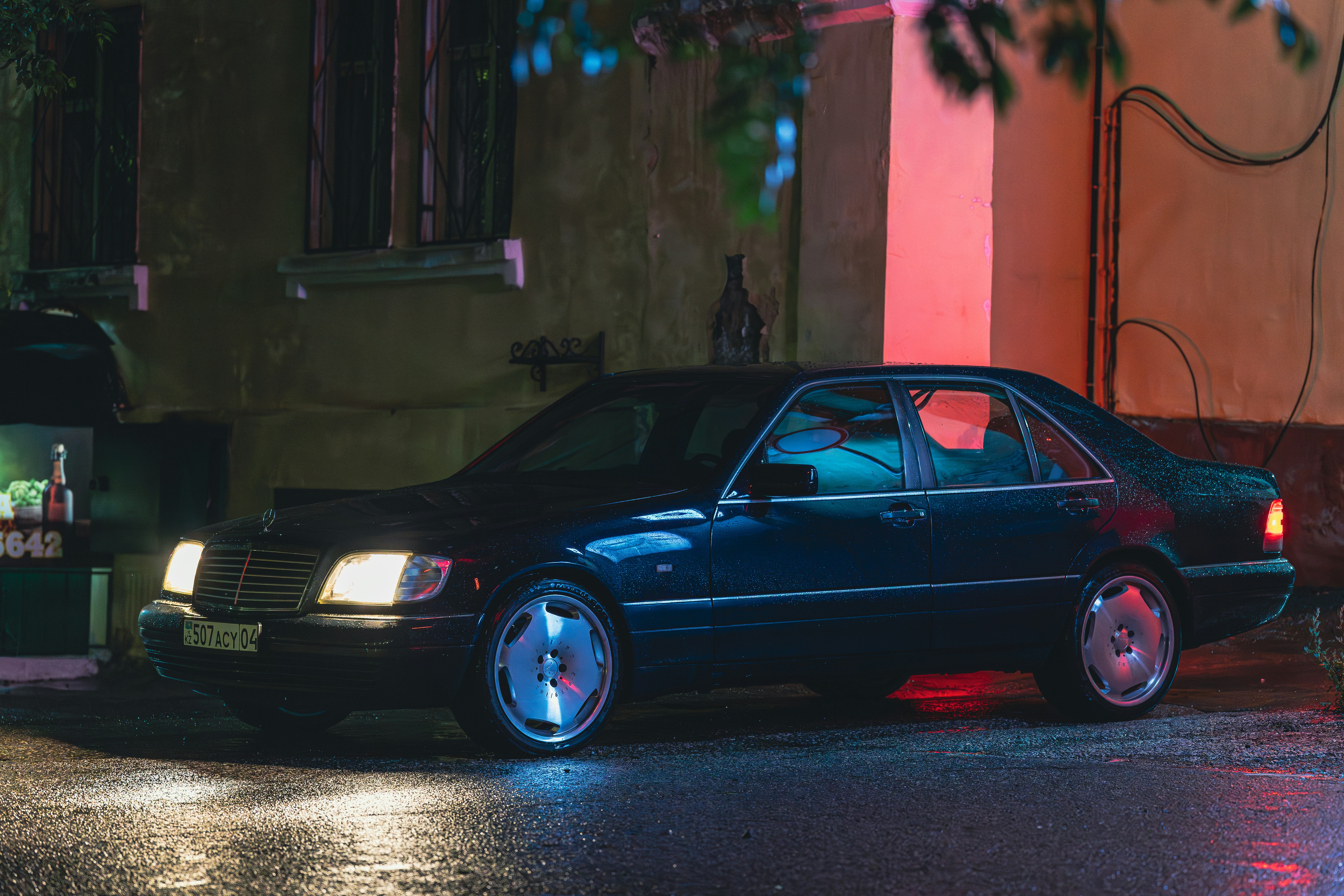 Neon Reflections on a Rain-Soaked City Sedan