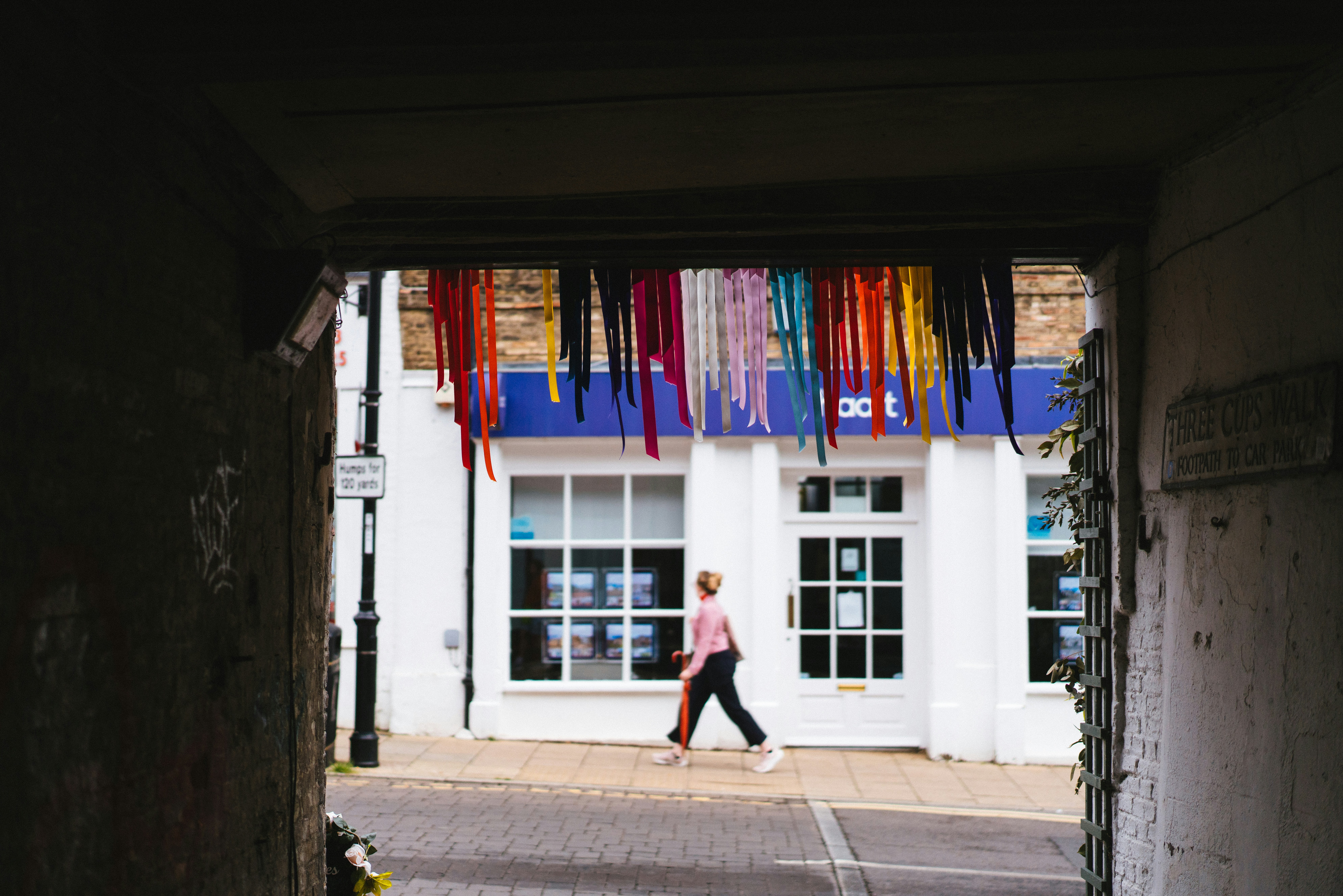 A woman walking down a street past a building photo – Free Street Image ...