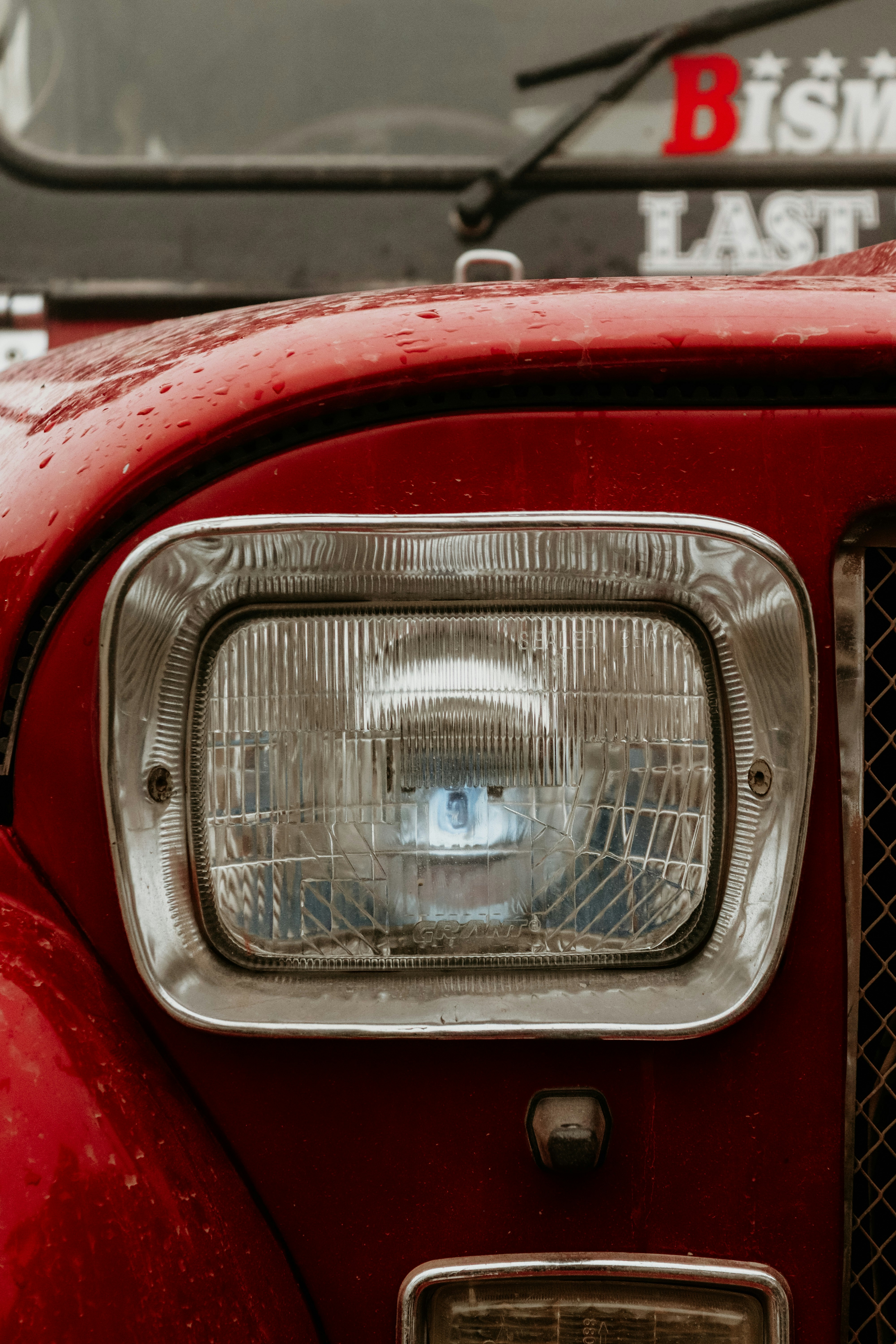 Grit Under Gloss: Close-Up of a Vintage Red Truck Headlamp