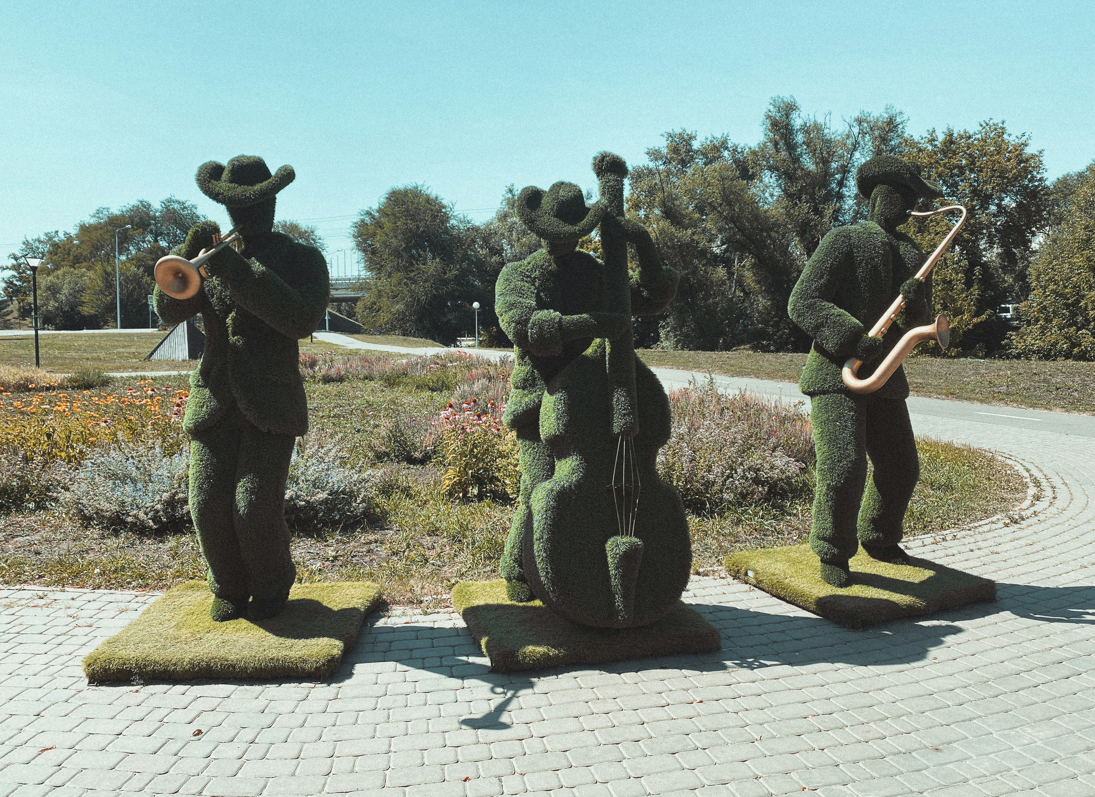 Topiary Trio Serenade Under a Sunlit Park Sky