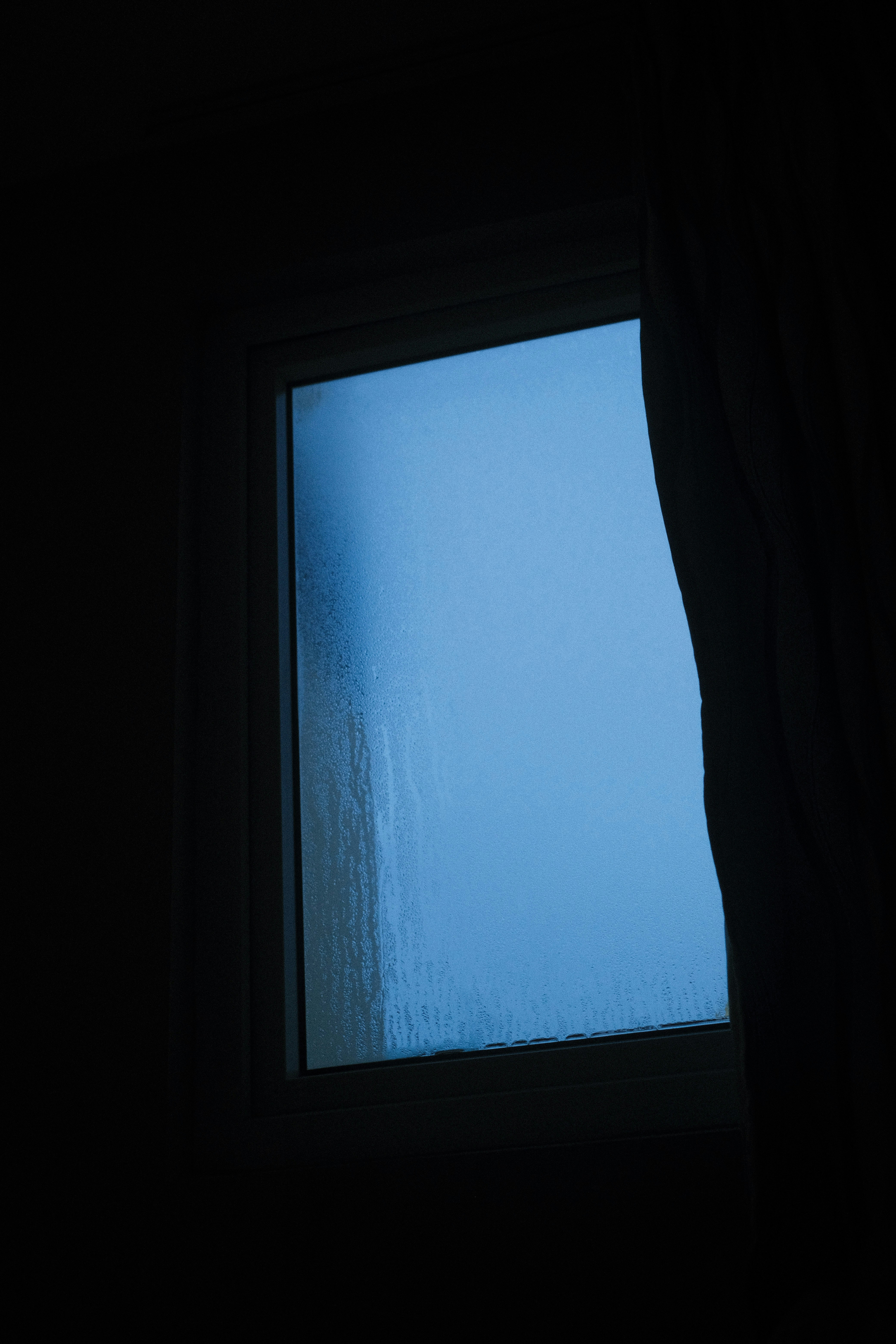A window in a dark room with a blue sky in the background photo – Free ...