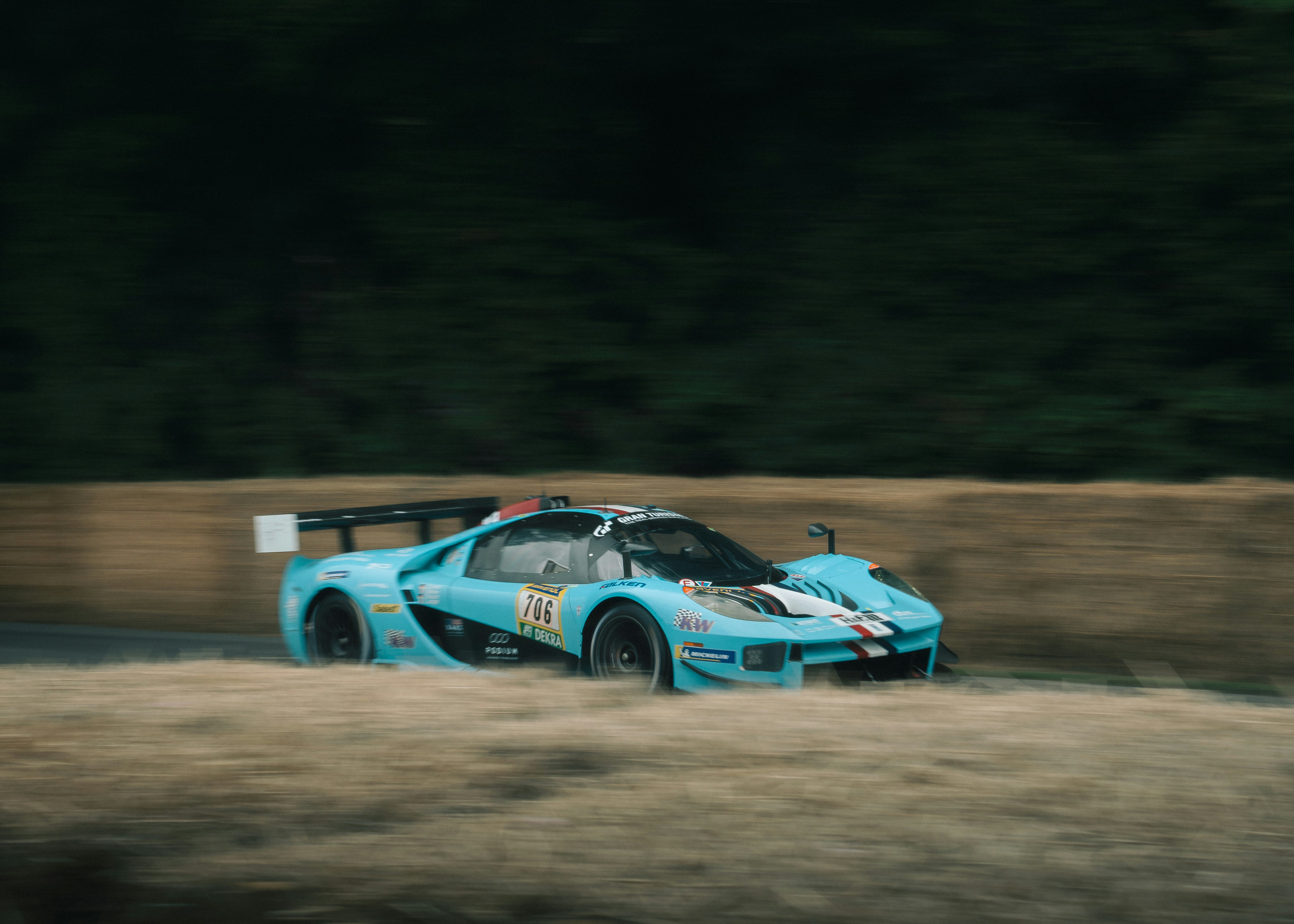 Azure Velocity: a blue race car slicing through a grass-swept track in motion