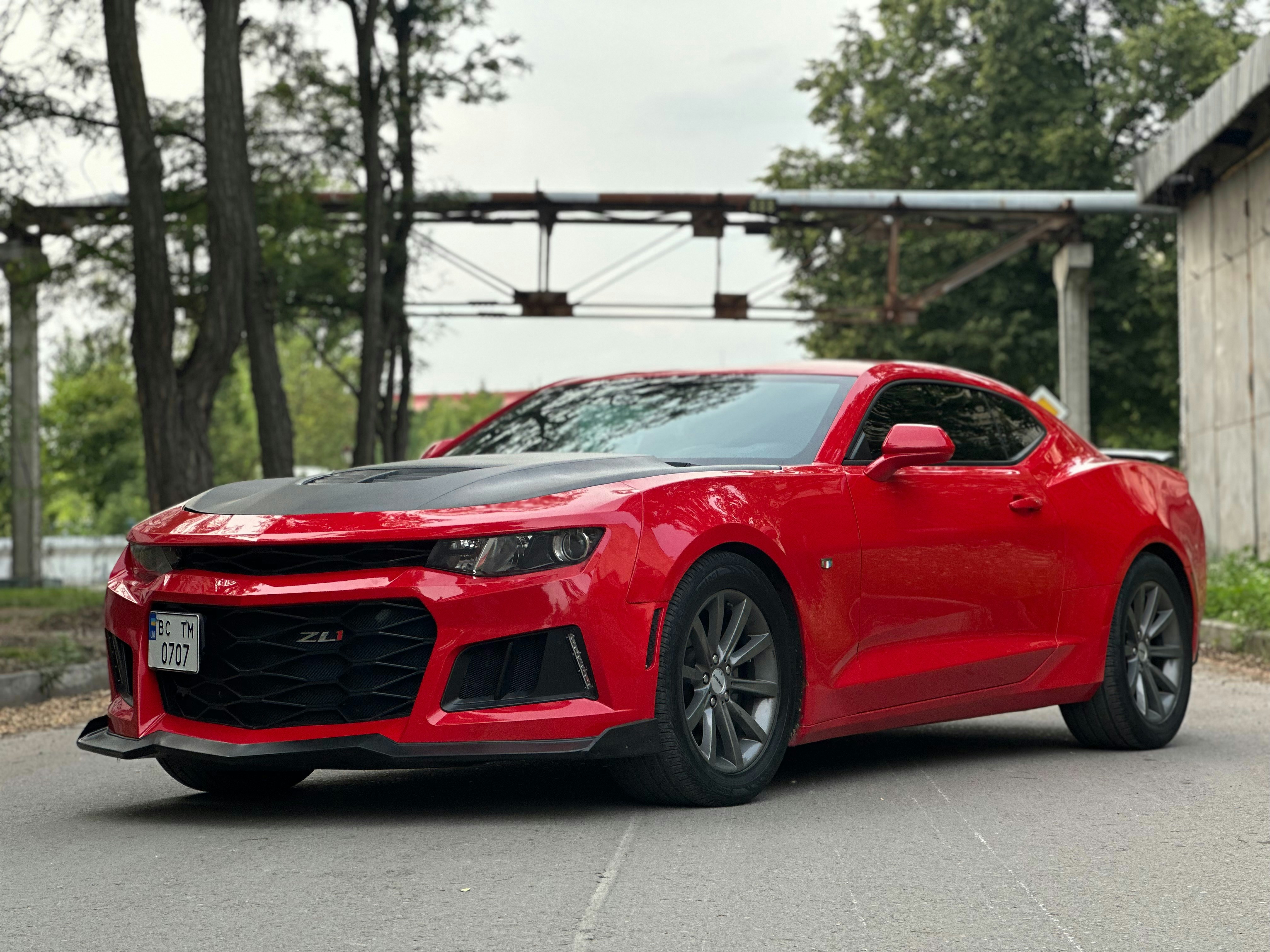 A red chevrolet camaro driving down a street photo – Free Україна Image ...