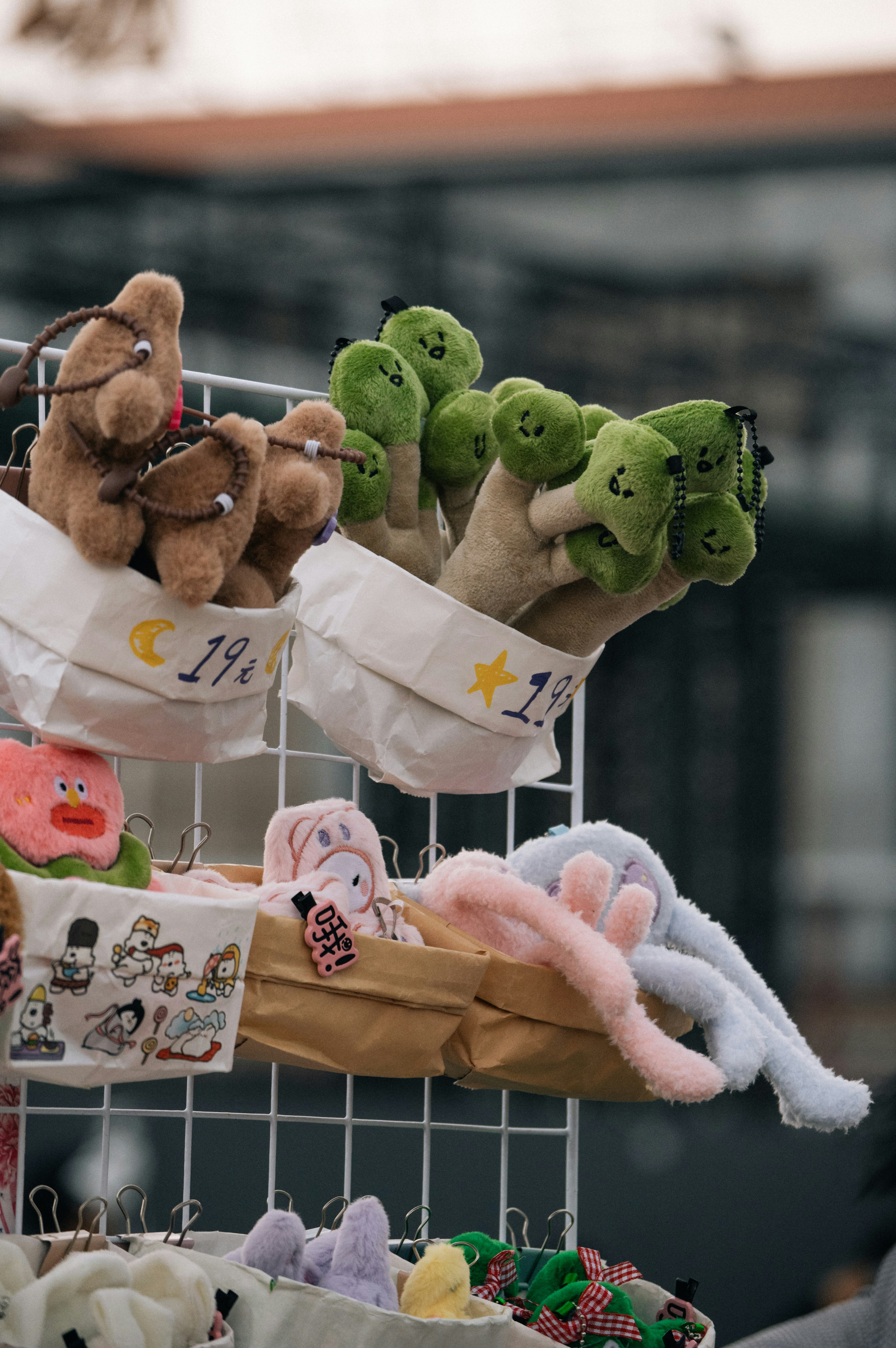 Whimsical Plush Window: Green Grins and Brown Buddies at Market Stall