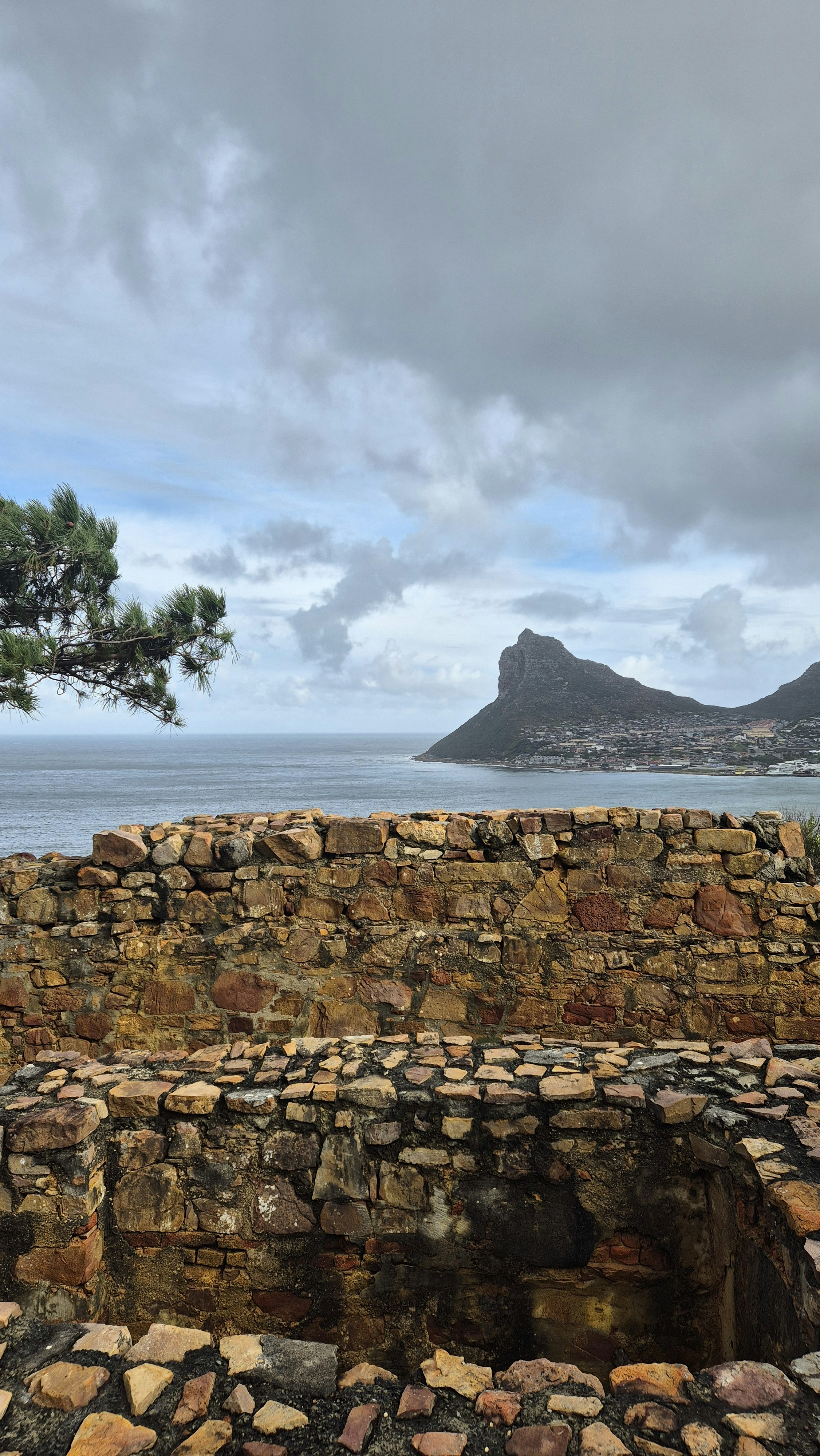 Ancient stone building ruins overlooking ocean and mountain