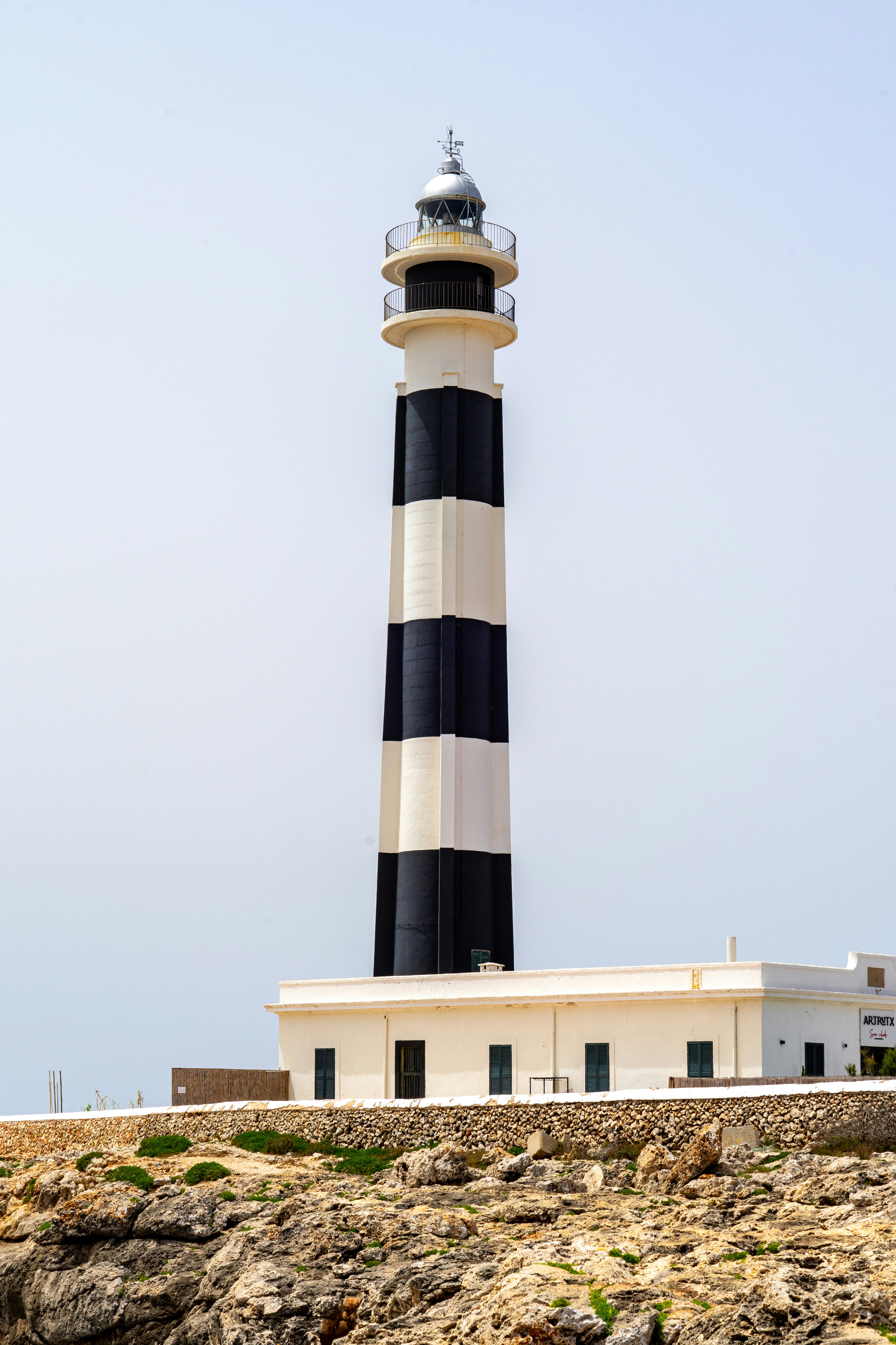 Striped Sentinel: Lighthouse Rising from the Rocky Coast