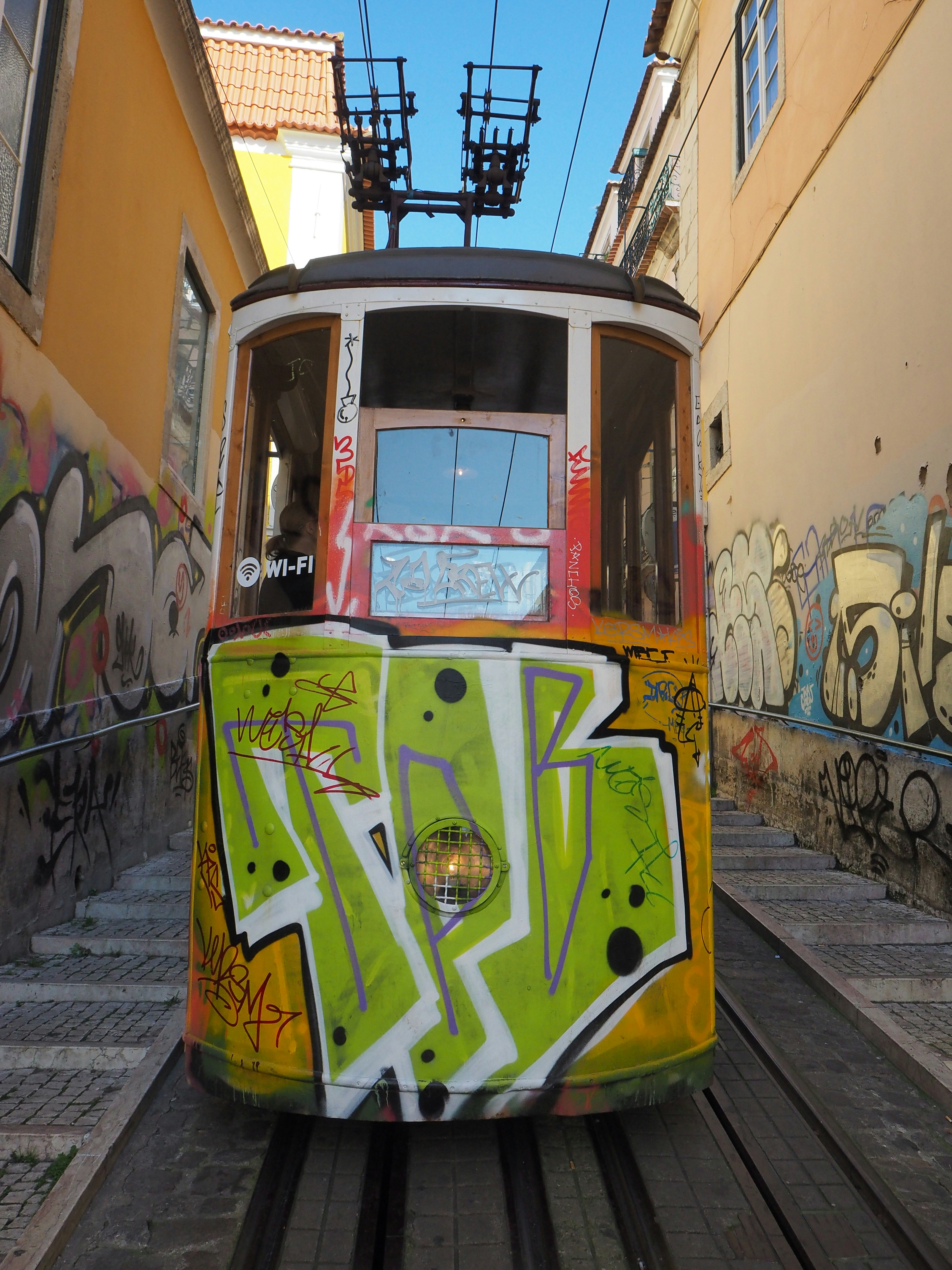 Graffiti-Wrapped Tram in a Sunlit Urban Alley