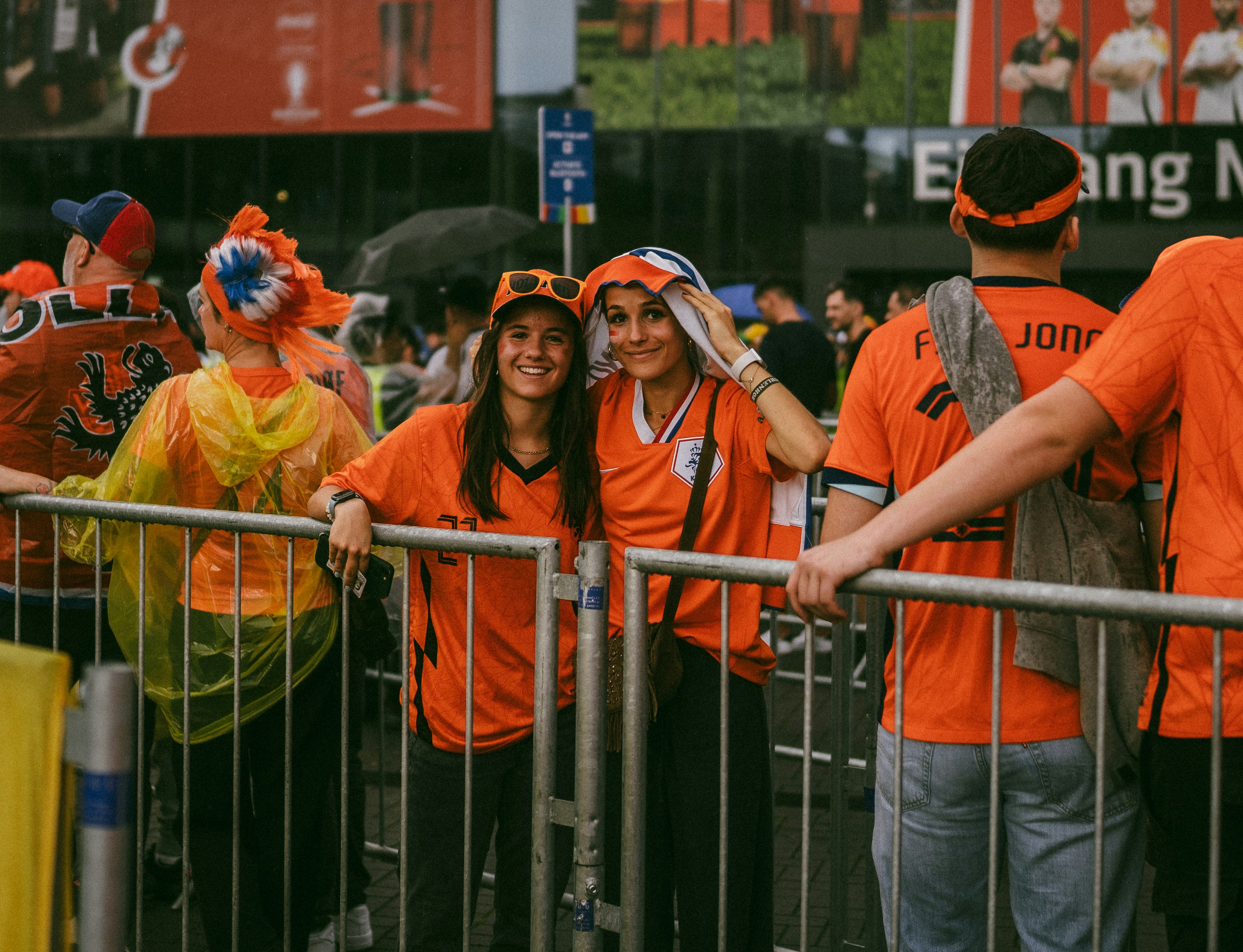 A group of people in orange shirts standing behind a fence photo – Free ...