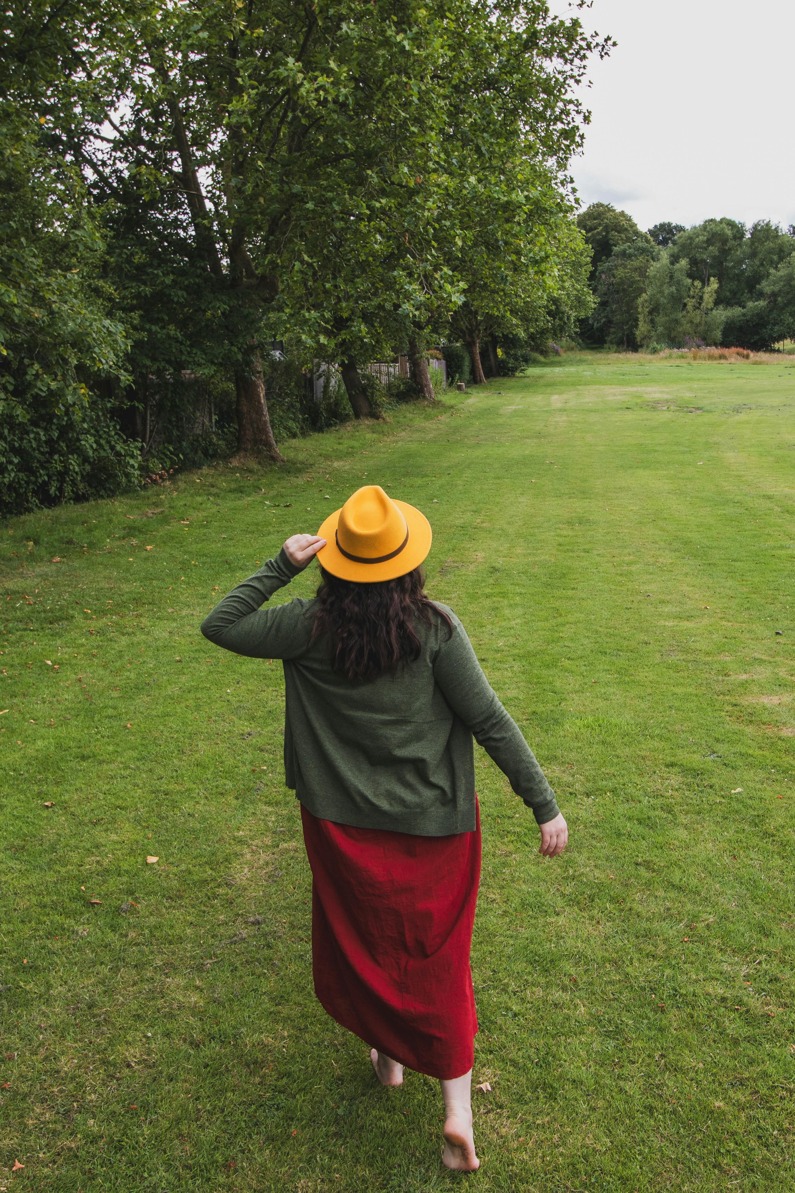 The Mustard Hat Crossing: A Solitary Stroll Across a Sunlit Meadow