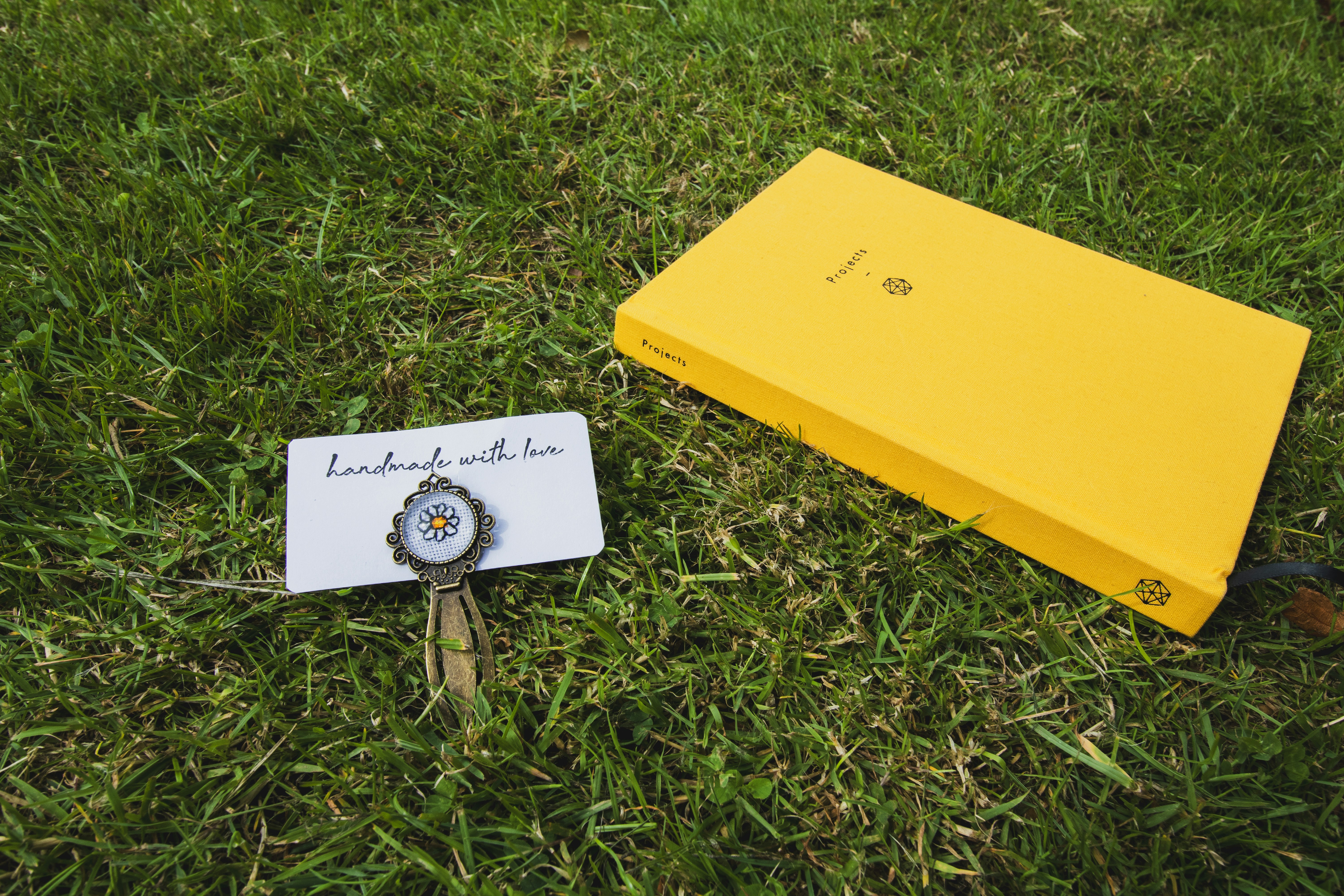 Tiny Floral Pendant by Handwritten Tag Beside a Bold Yellow Box on Grass