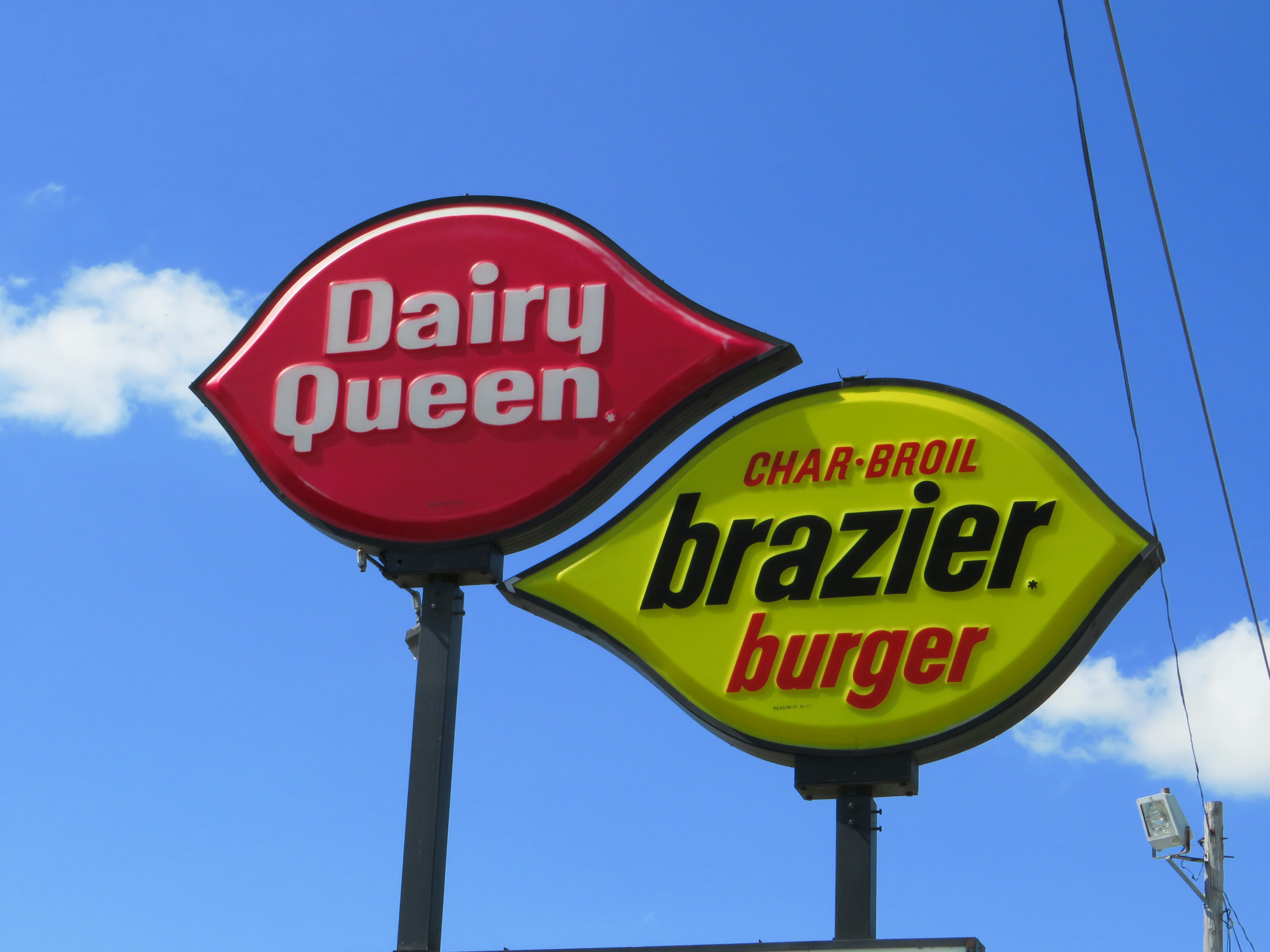 Dairy Queen & Brazier Burger Sign Duo Against a Bright Sky