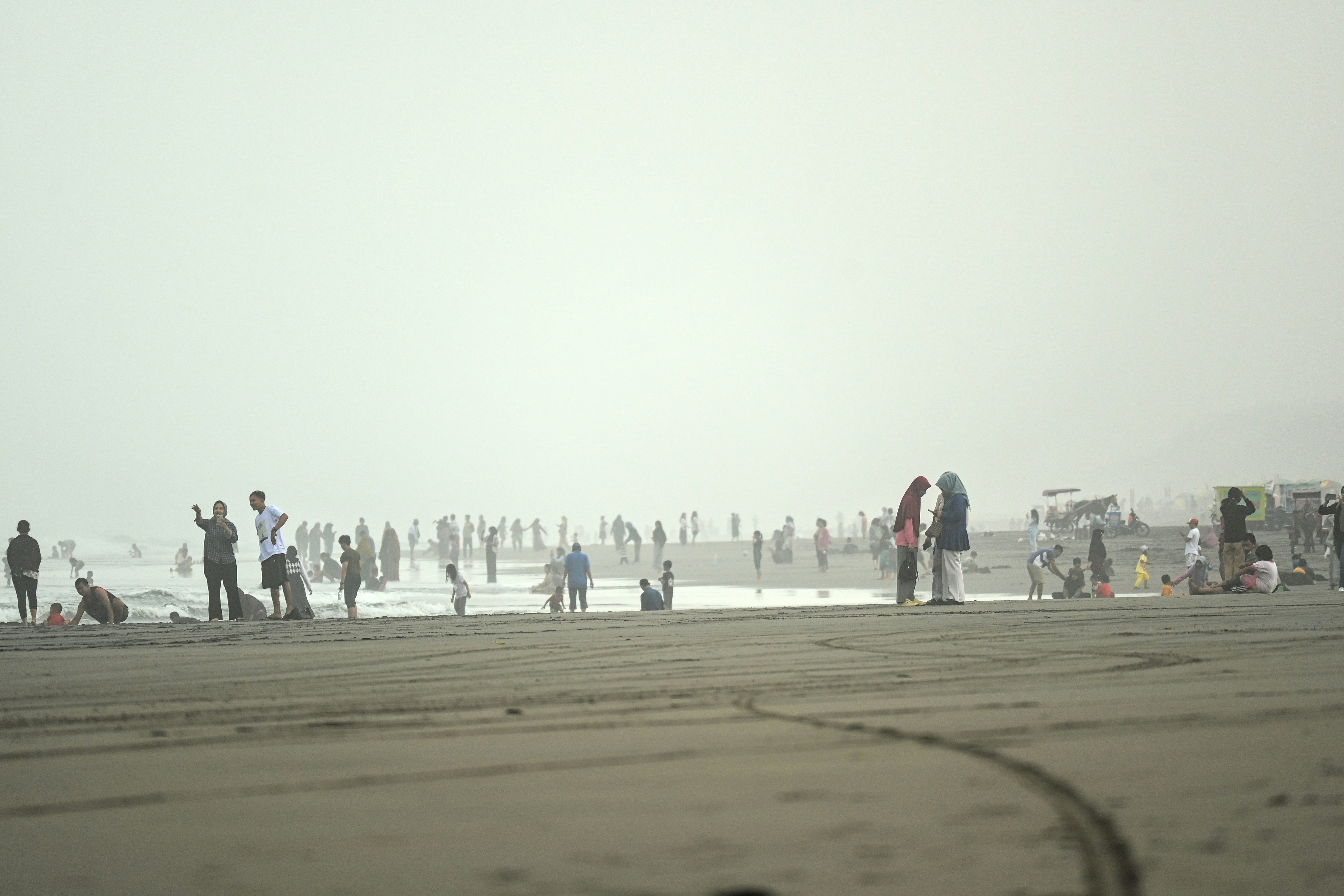 Haze Over the Shore: Silhouettes on a Busy Beach
