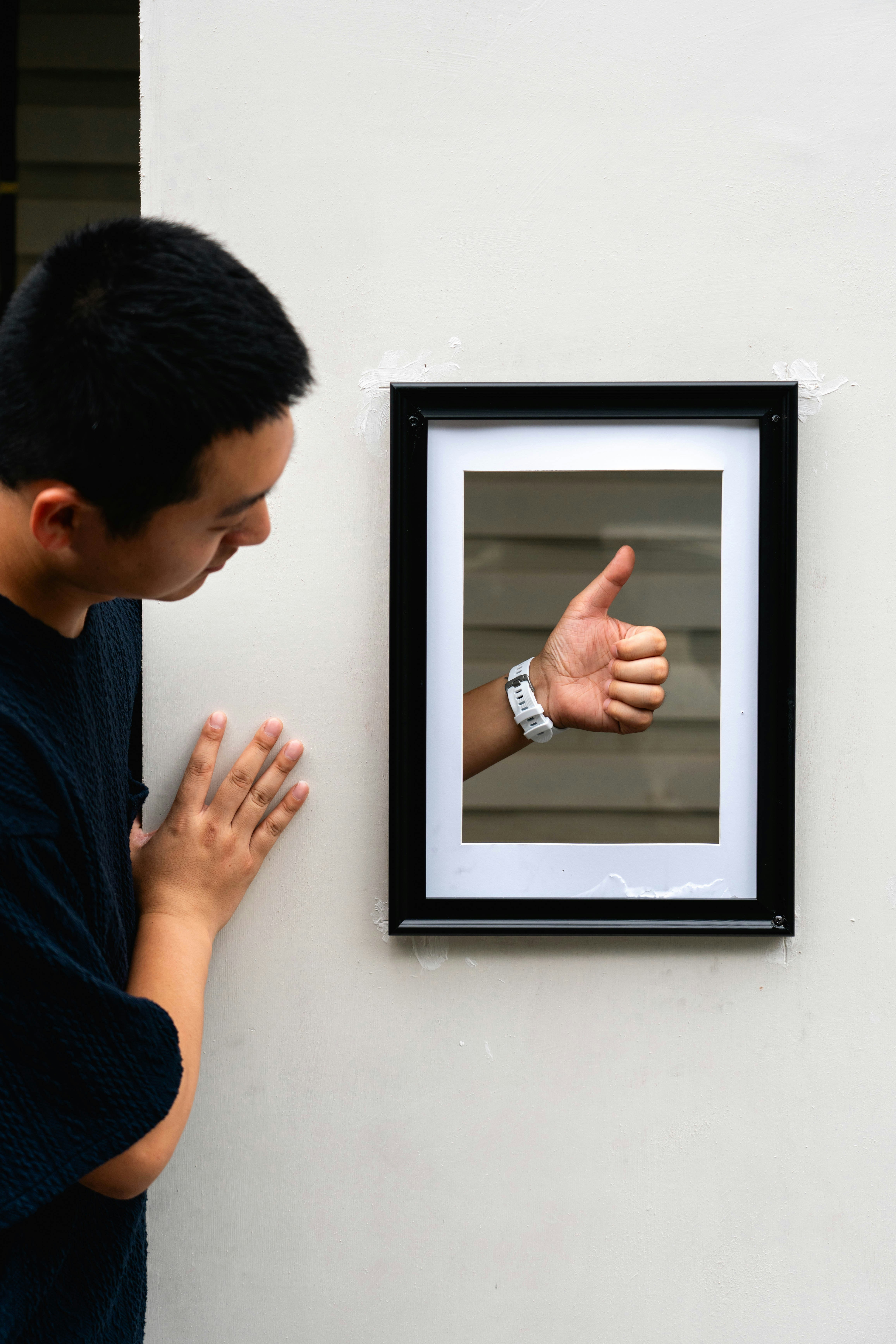 Thumbs-Up in a Framed Moment: A Quiet Portrait by the Wall
