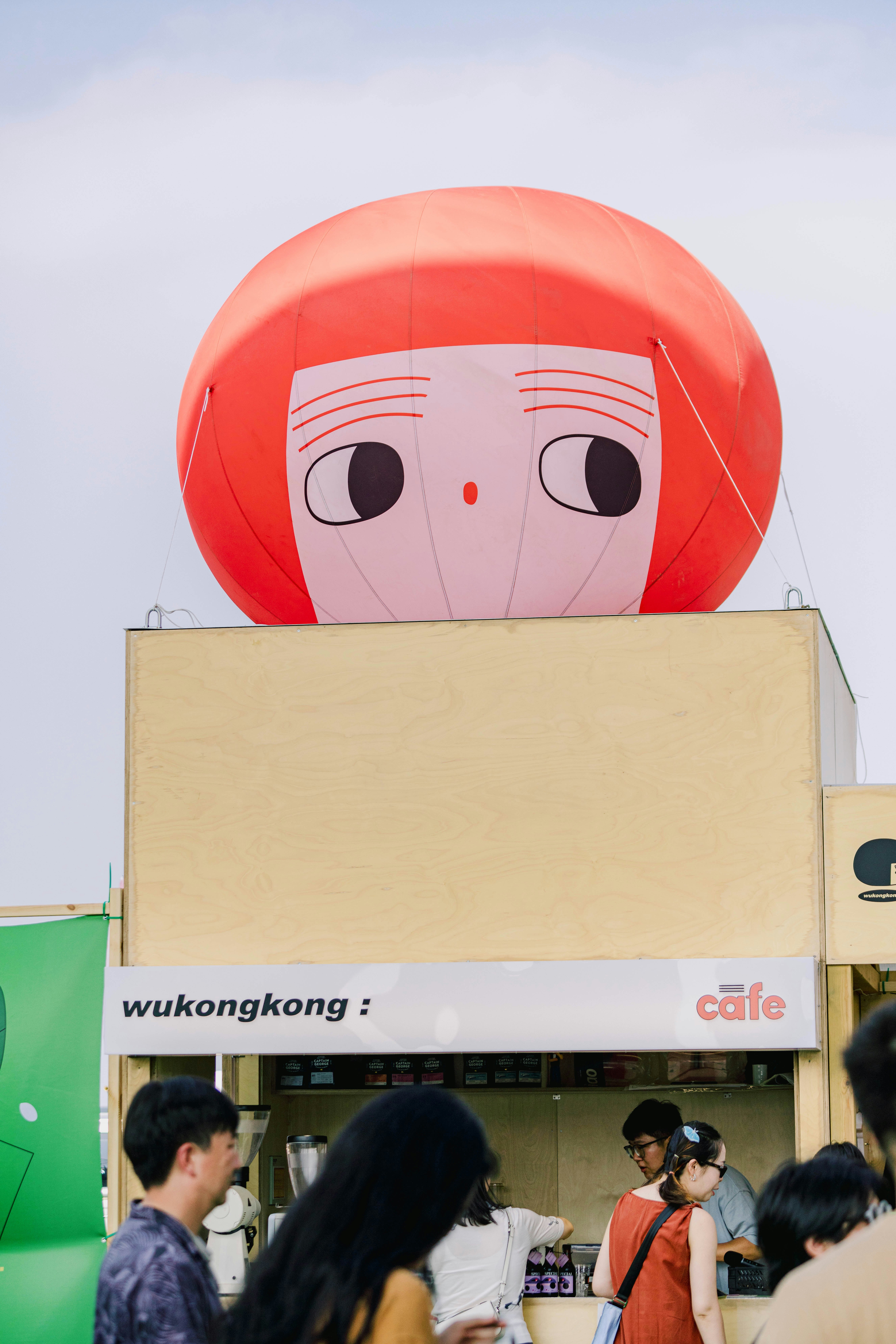 Giant Cartoon Head Over a Street Café Stall