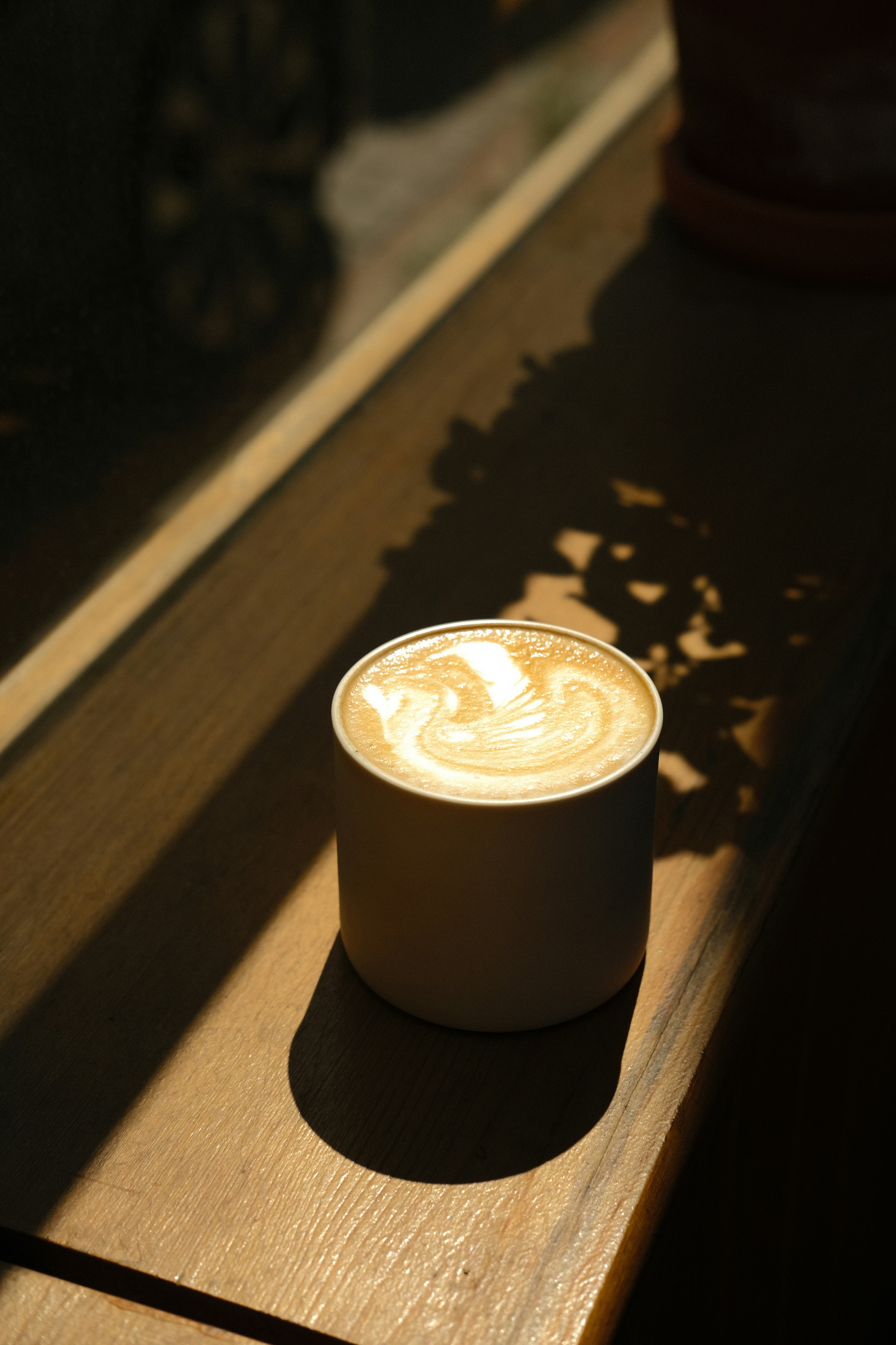 Sunlit Cup: Latte Art on a Wooden Counter