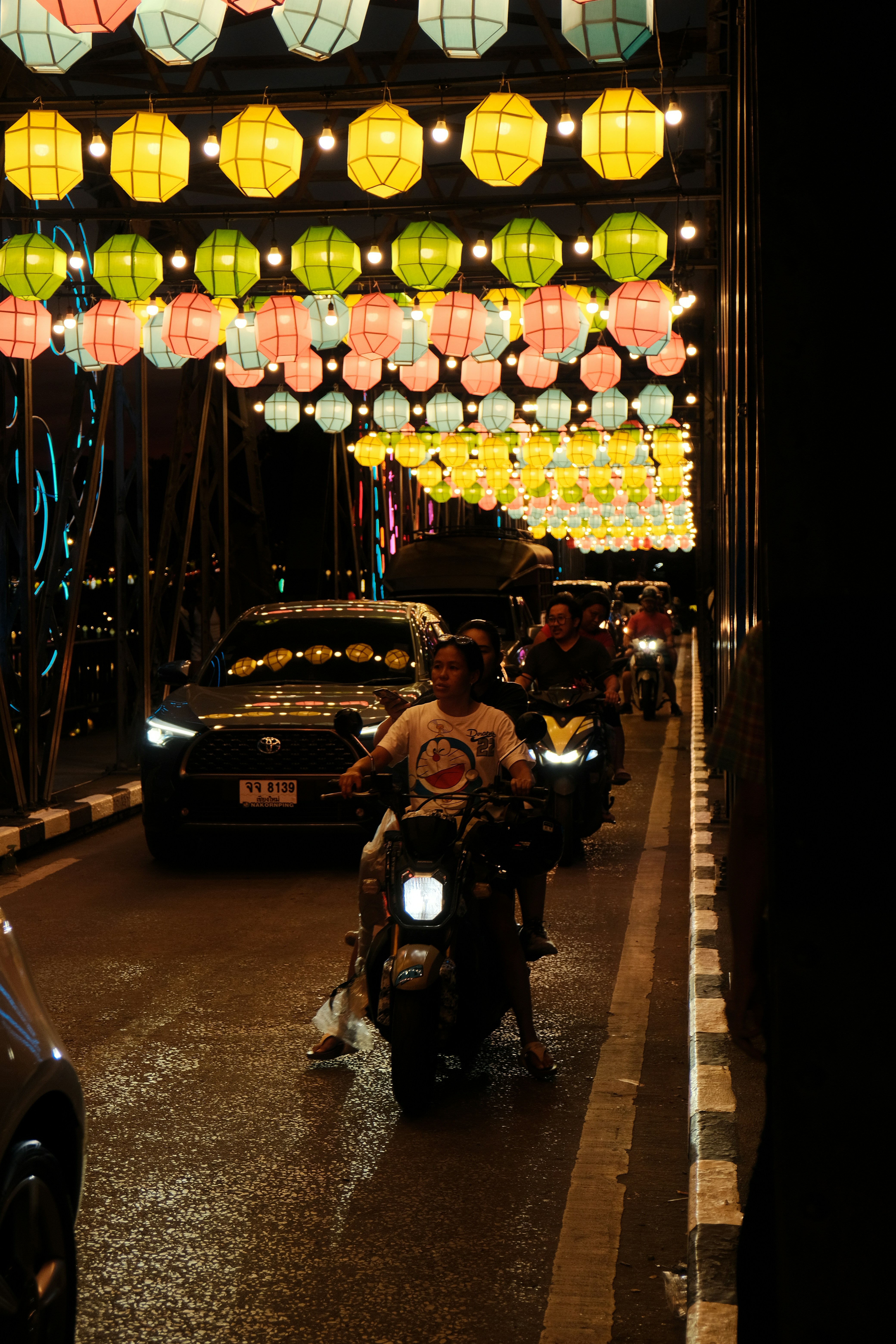 A man riding a motorcycle down a street under lanterns photo – Free ...