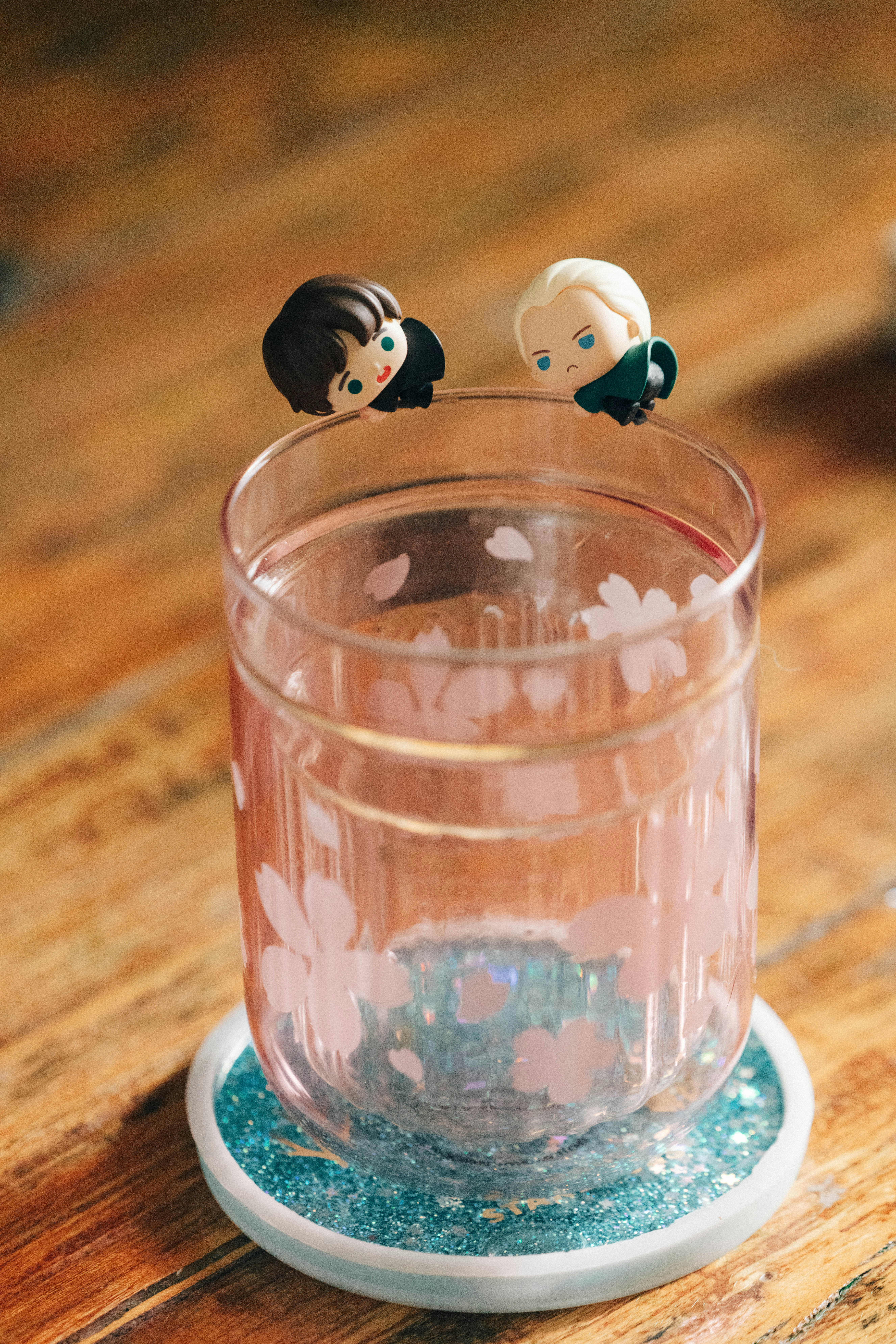 Edge-of-the-Glass Guardians: A Miniature Duo Perches on a Pink Floral Glass