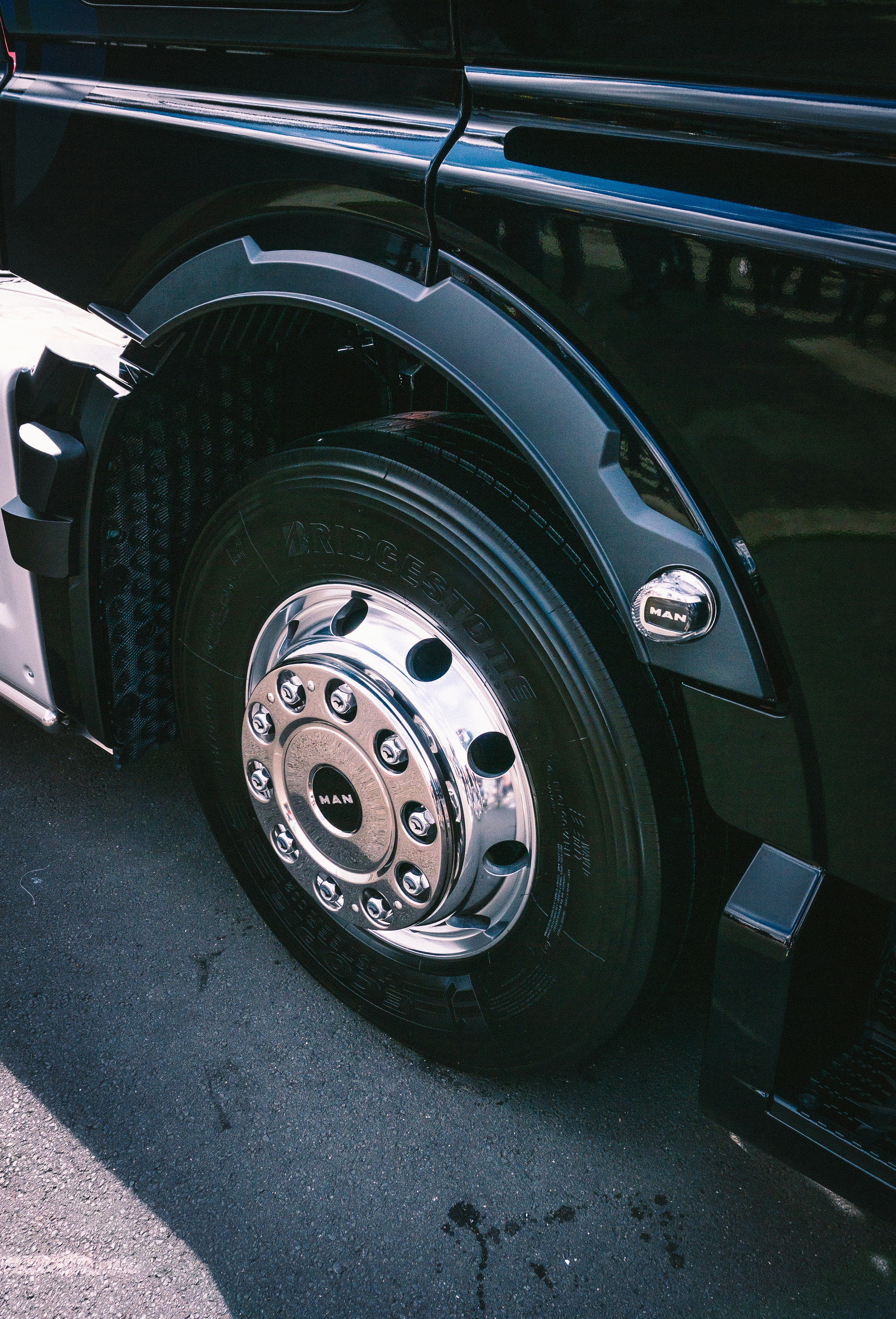 Chrome Hub Portrait: A Close-Up of a MAN Truck Wheel on a Gleaming Black Panel