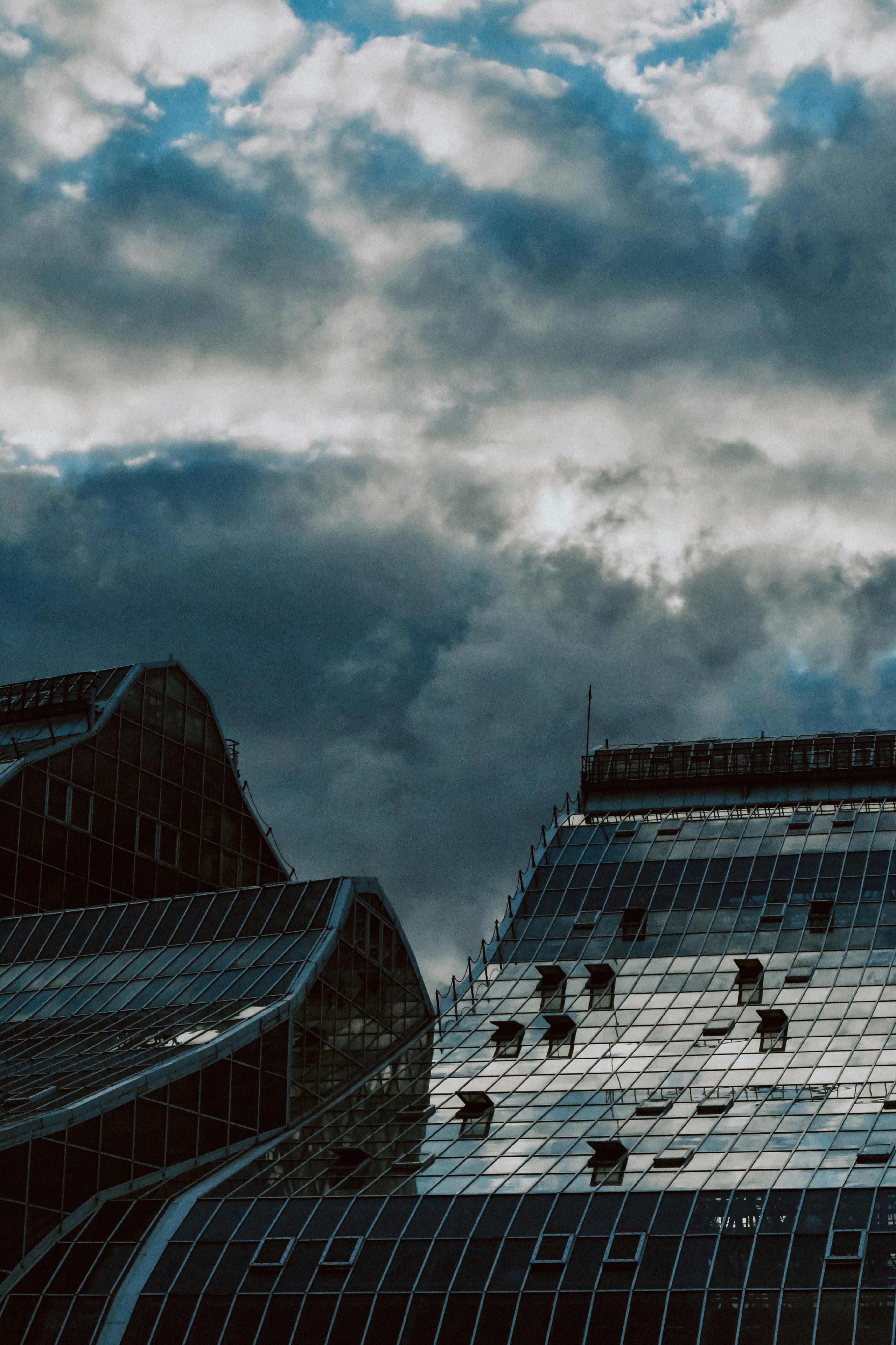 Moody Facades: Reflections and Steel Under Stormy Skies